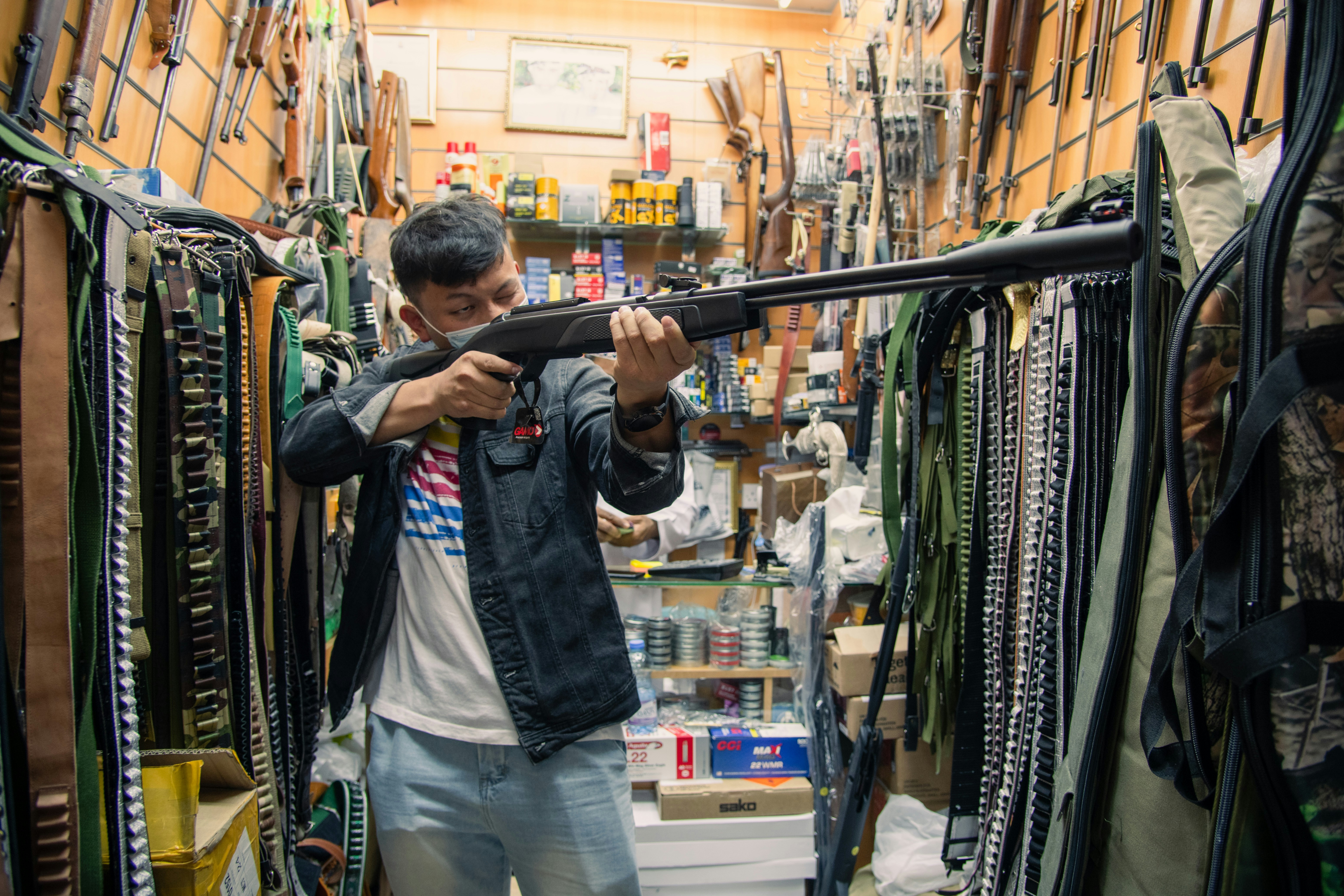A man holding a rifle inside of a store photo – Free Person Image on ...