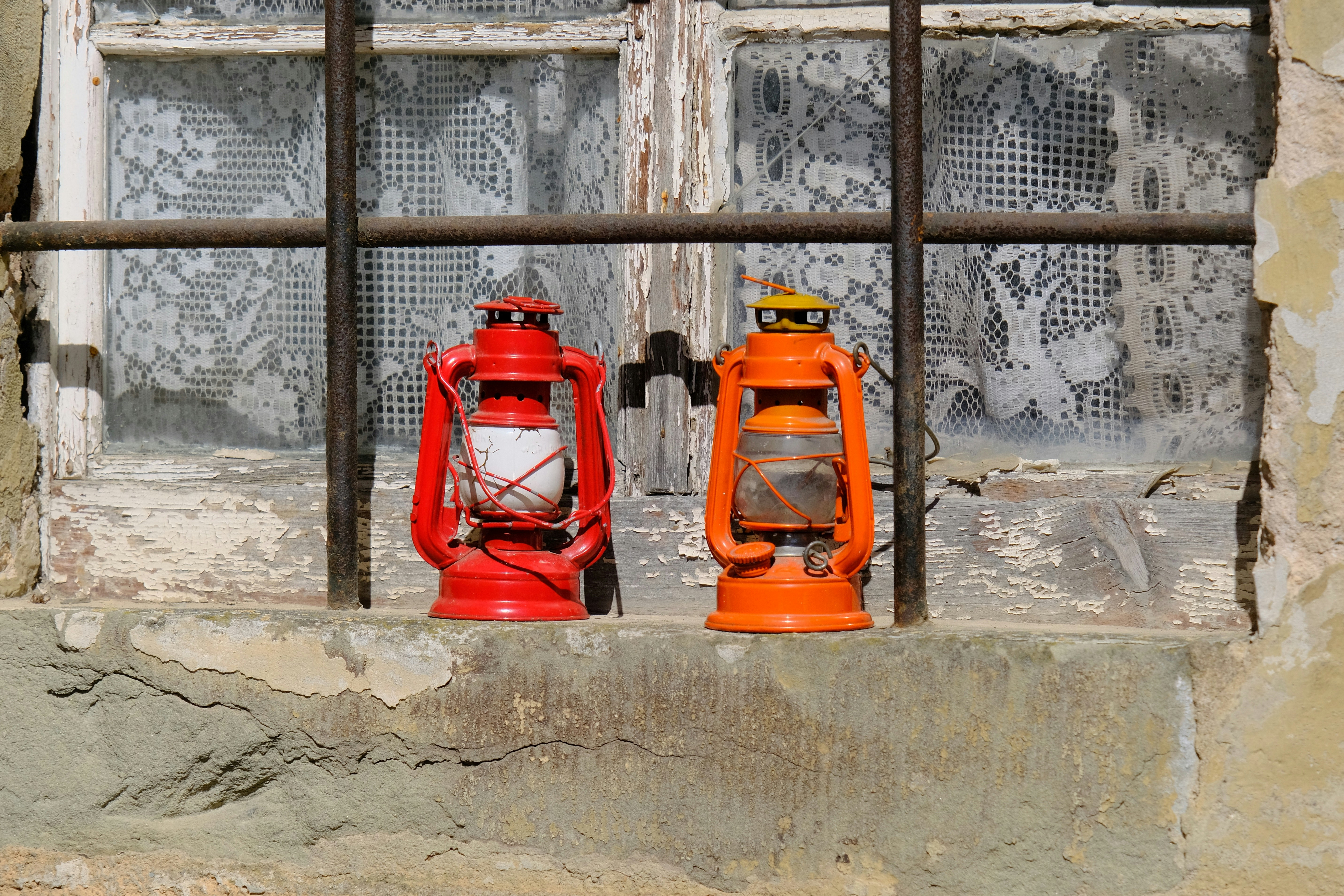 Two Vintage Lanterns Guarding a Crumbling Window