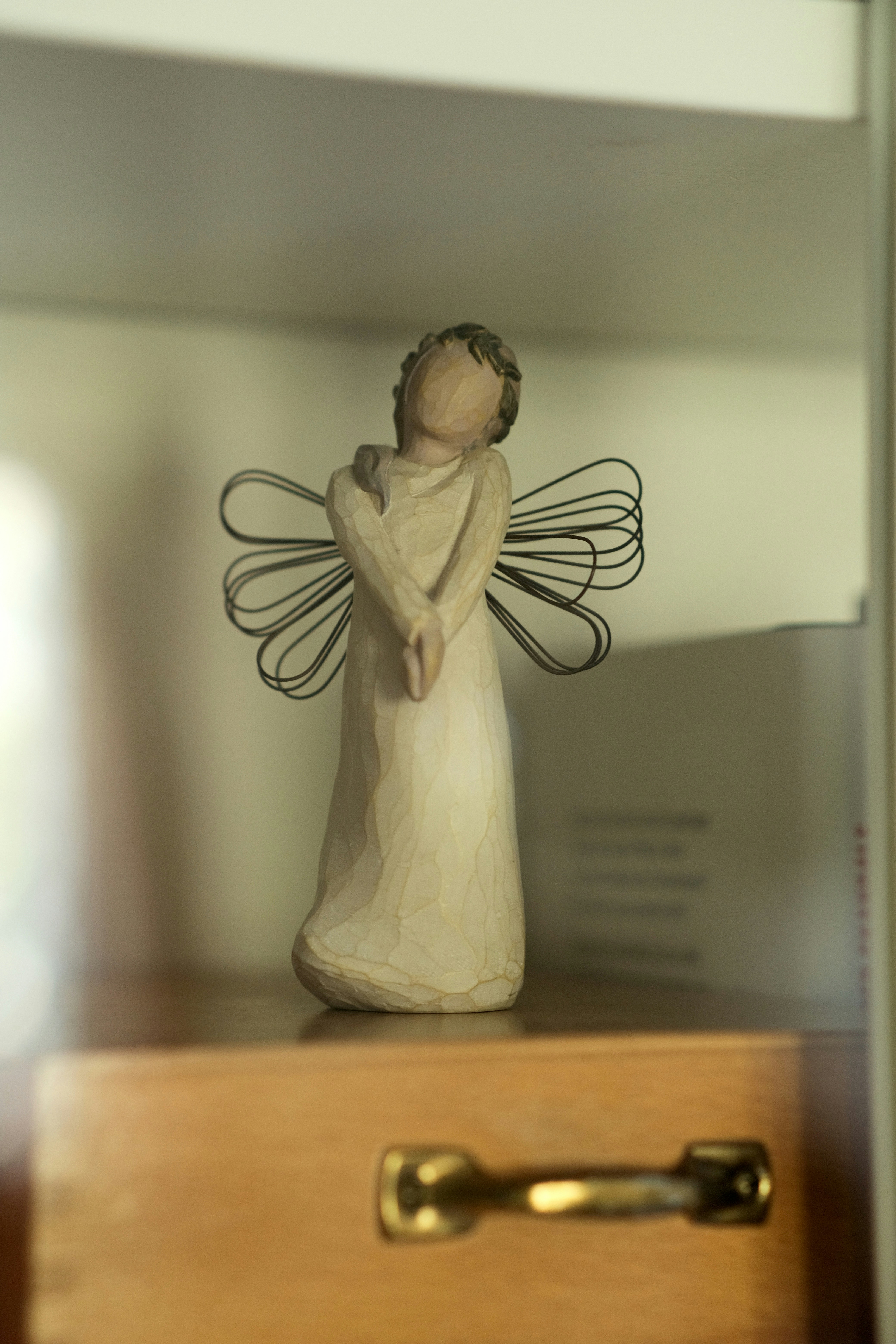 A delicate wooden angel figurine with wire wings, exuding a sense of calm and protection, set against a softly blurred background.