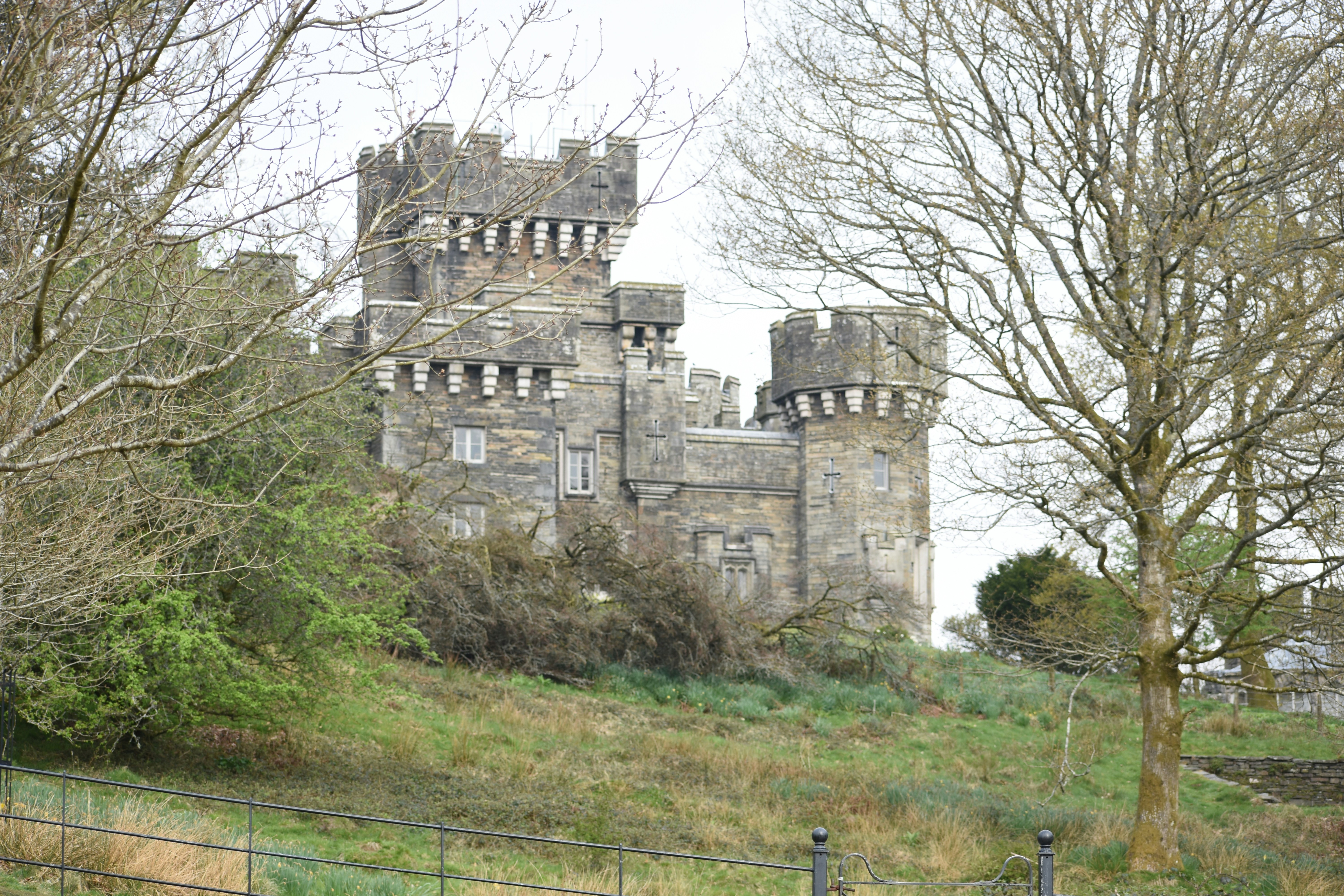 A large stone castle sitting on top of a lush green hillside photo ...