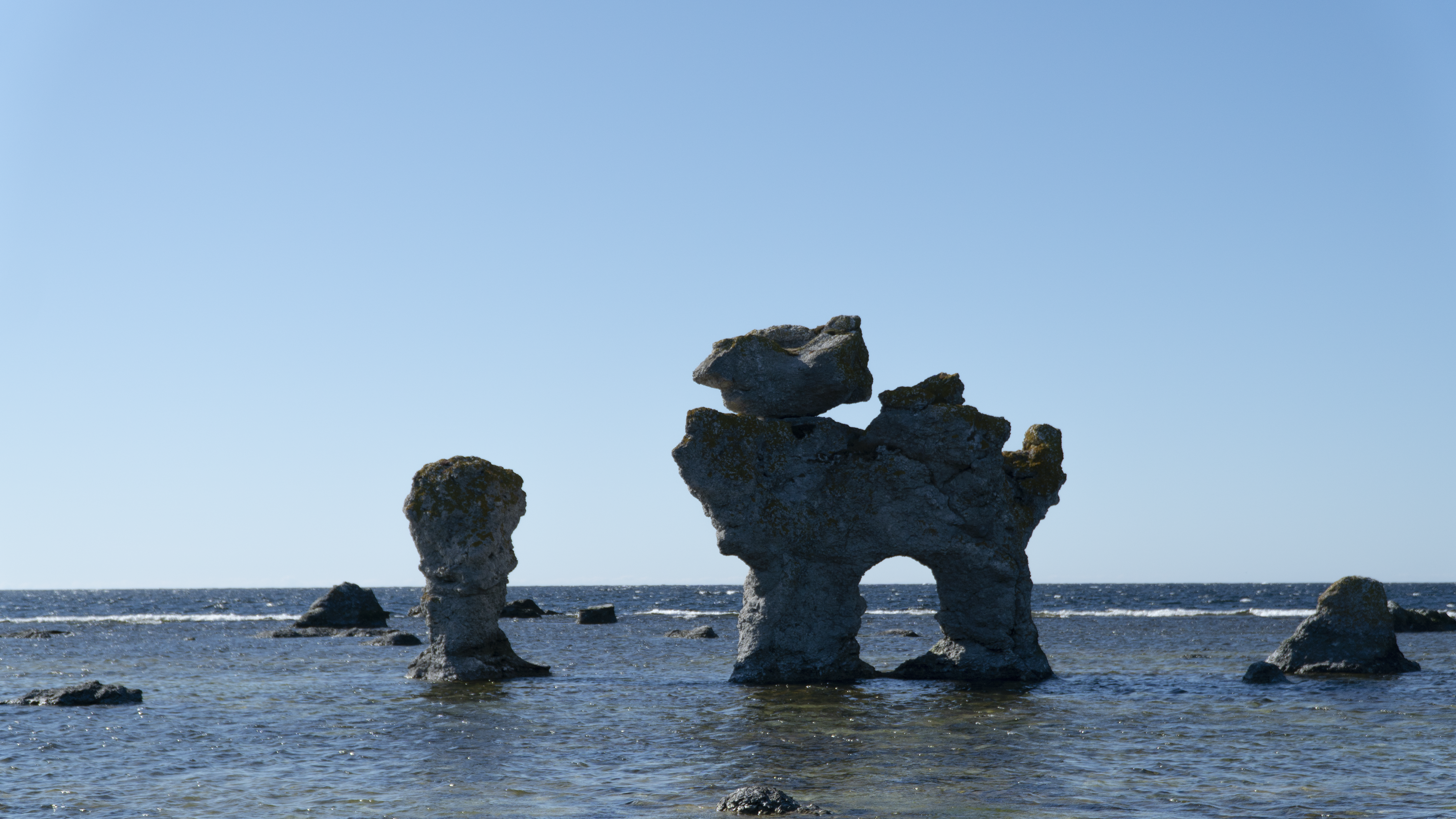 Eine Gruppe von Felsen im Wasser mit einem Himmelshintergrund Foto ...