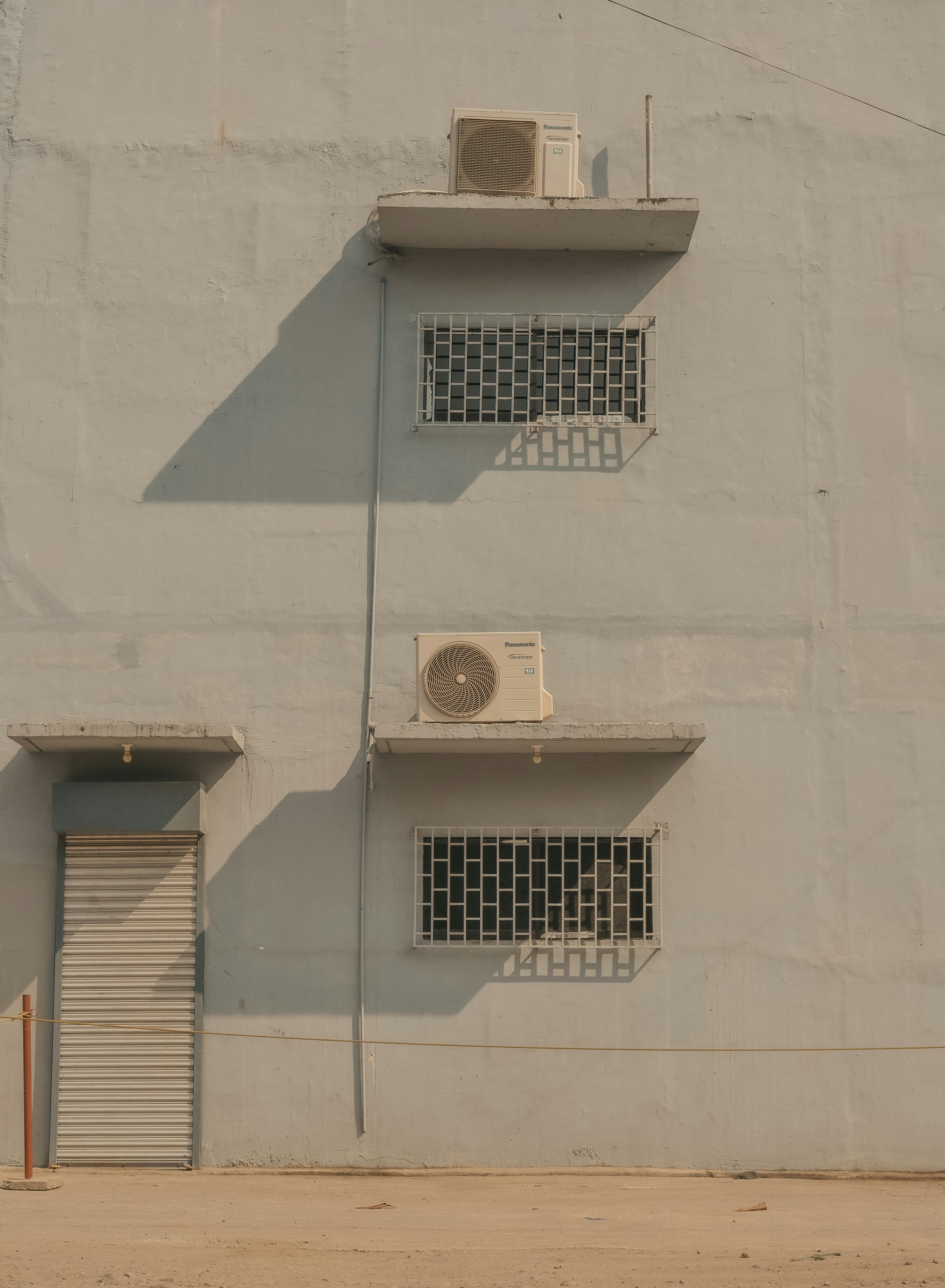 Sun-bleached Facade: Two AC Units and Gridded Windows in Quiet Light