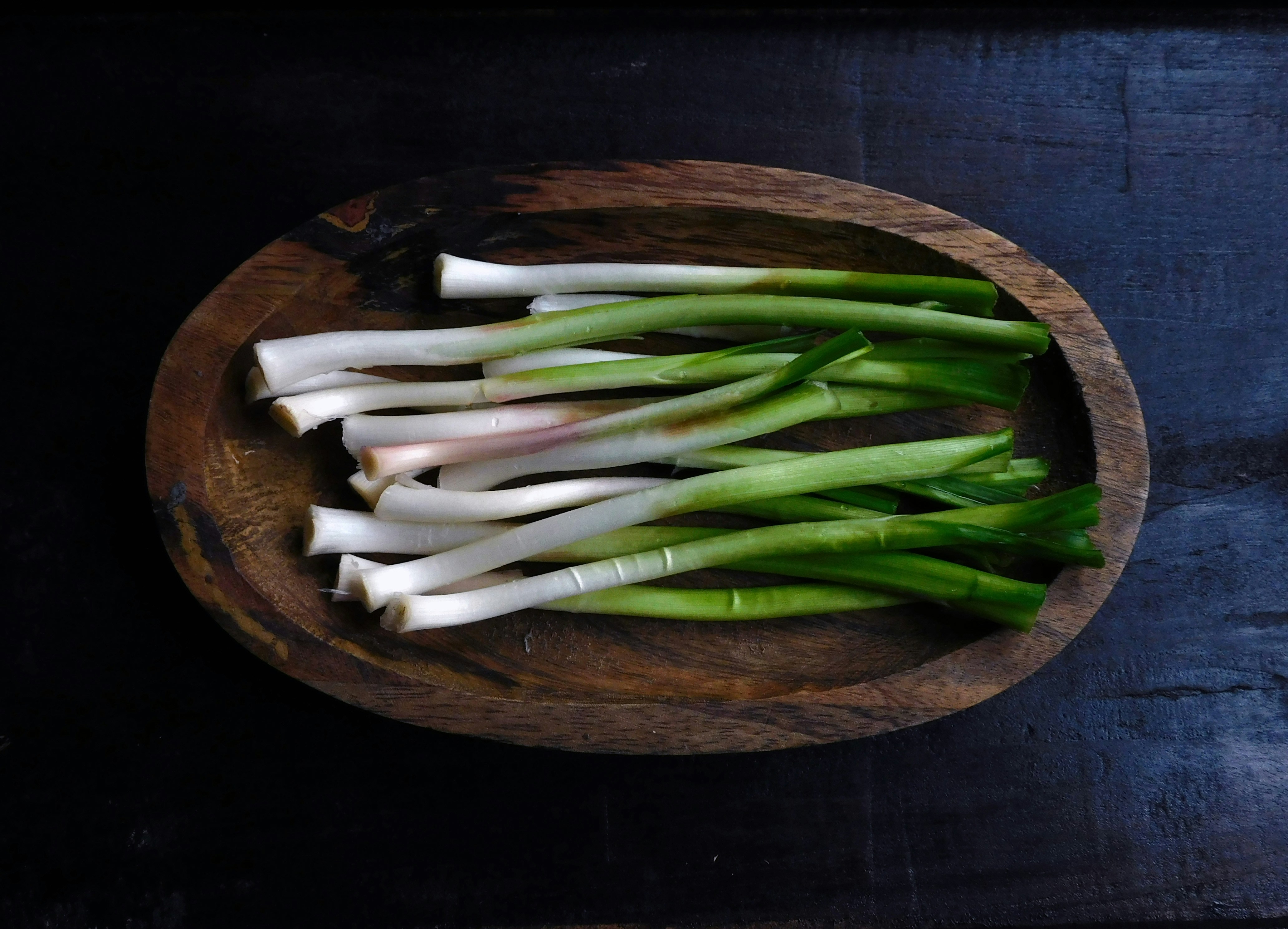a wooden bowl filled with green and white onions