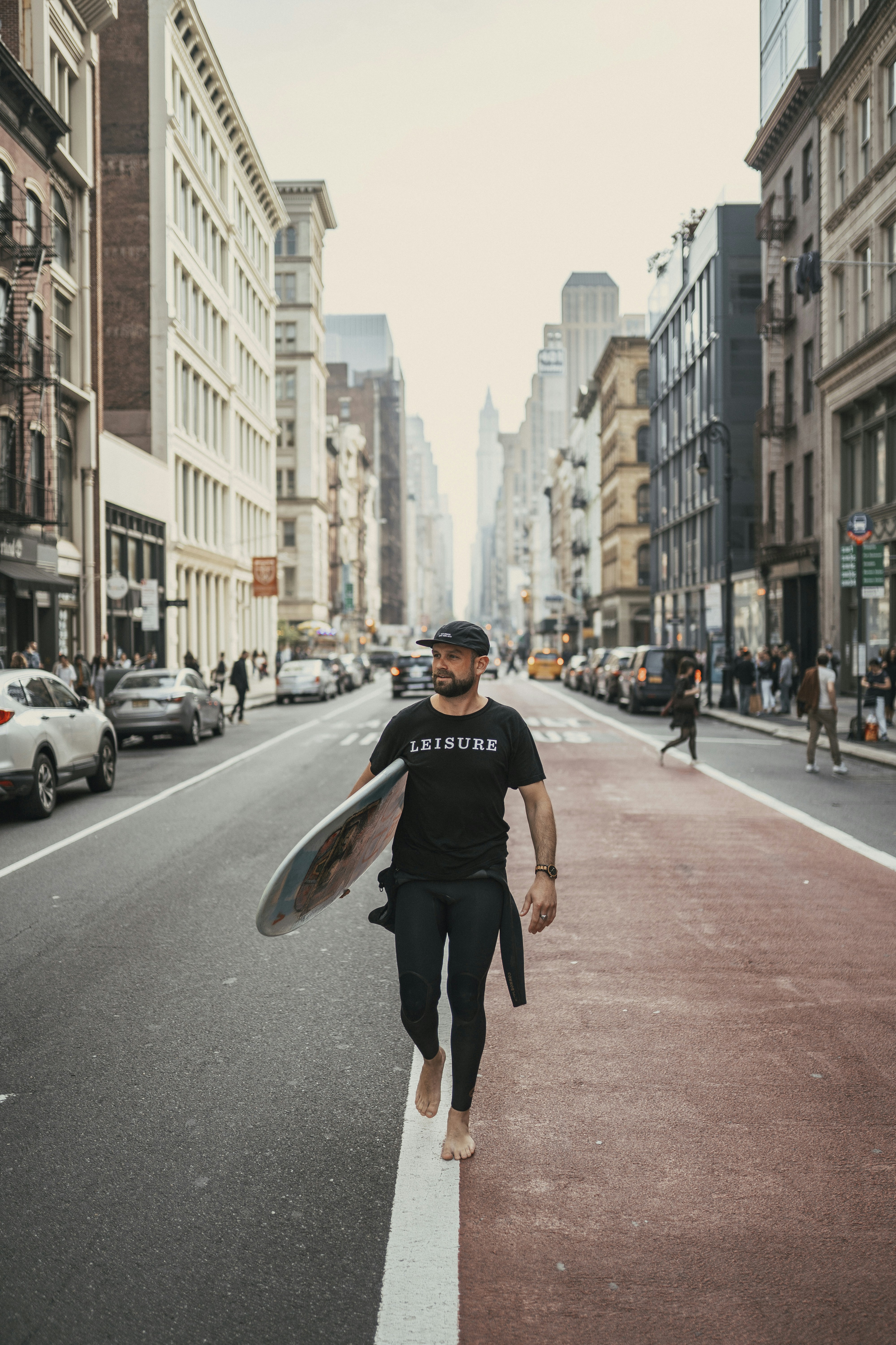 a man walking down a street holding a surfboard