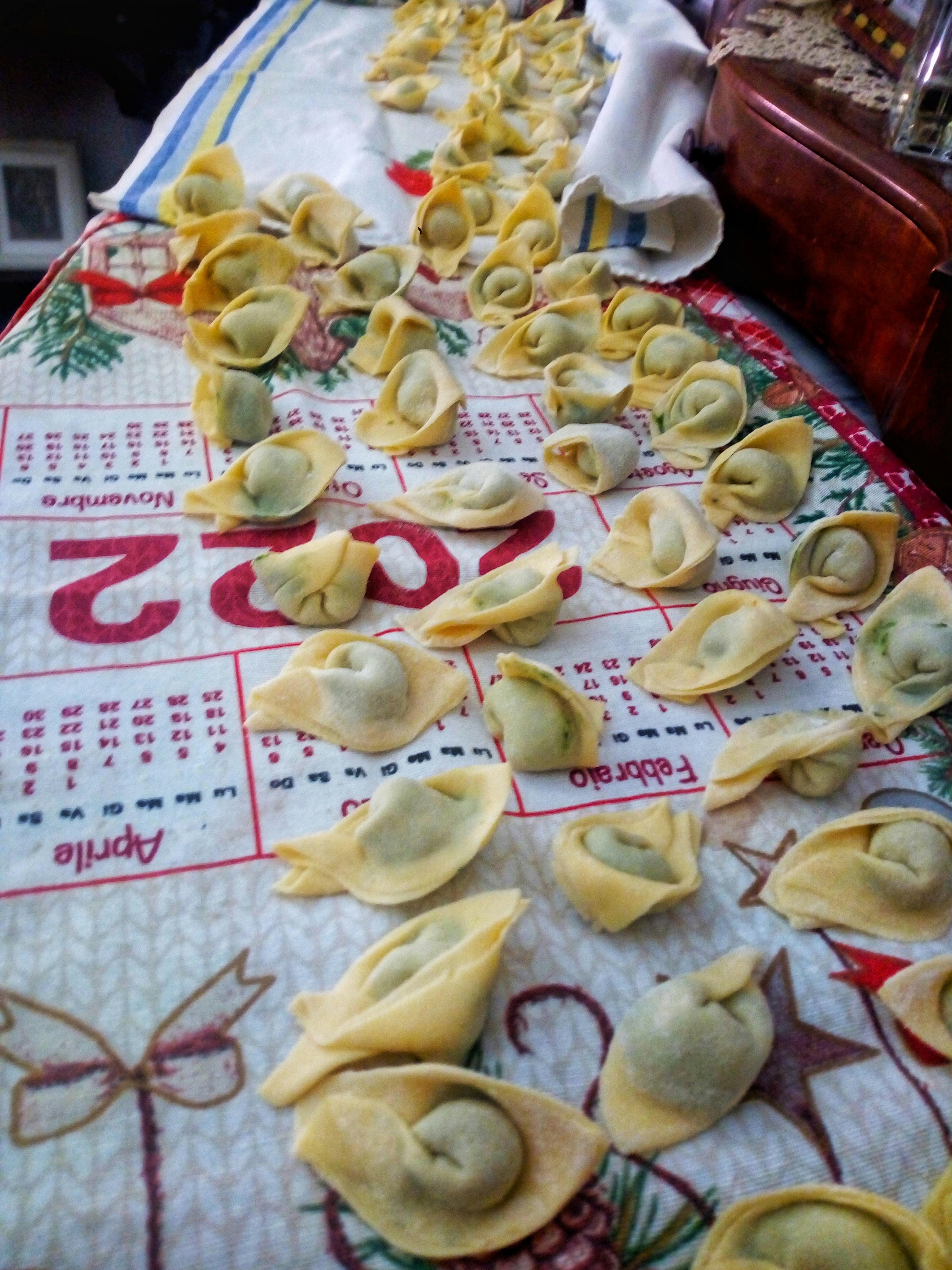 Rows of fresh pansoti pasta arranged on a festive tablecloth.