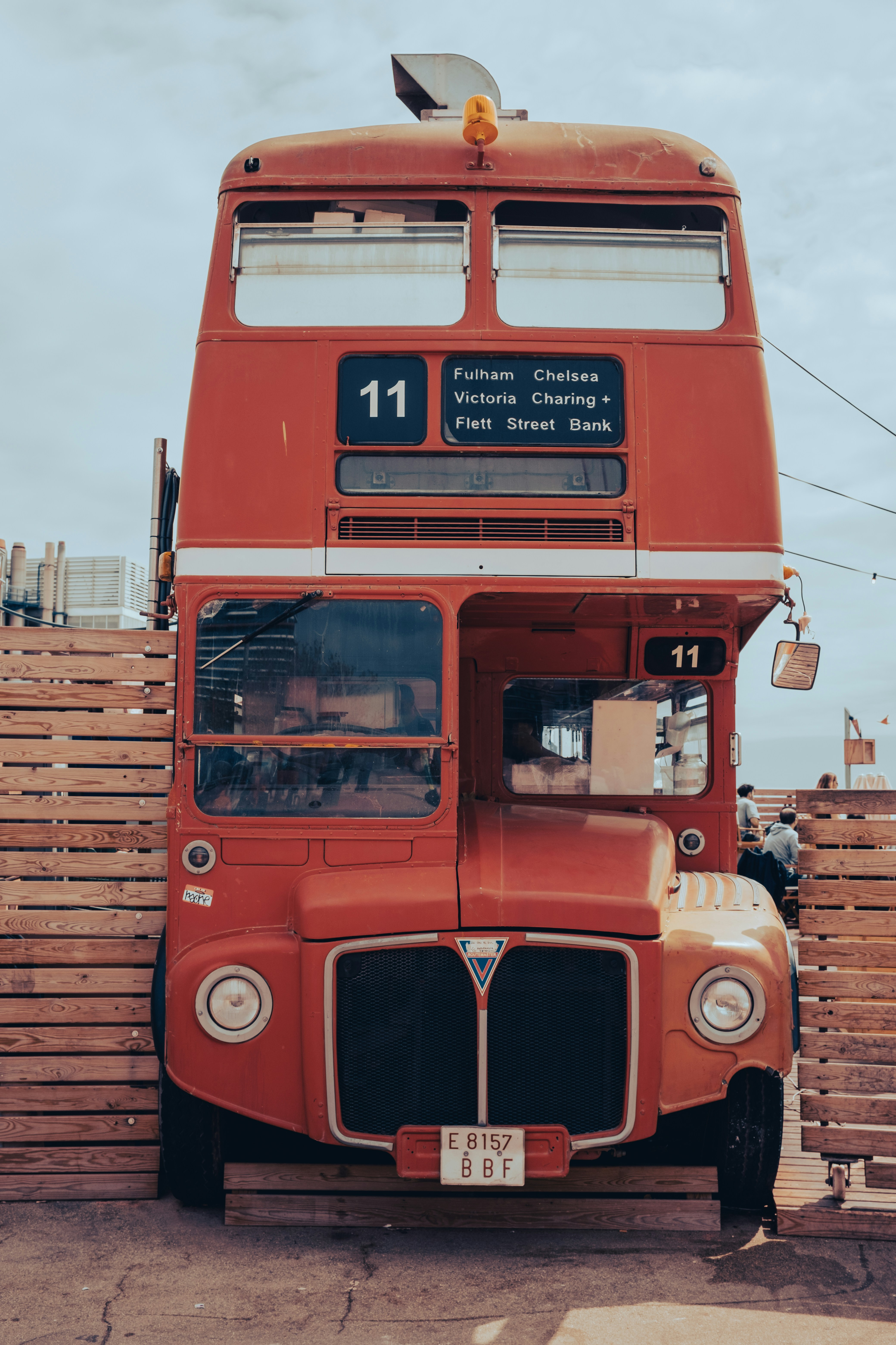 A red double decker bus parked next to a wooden fence photo – Free ...