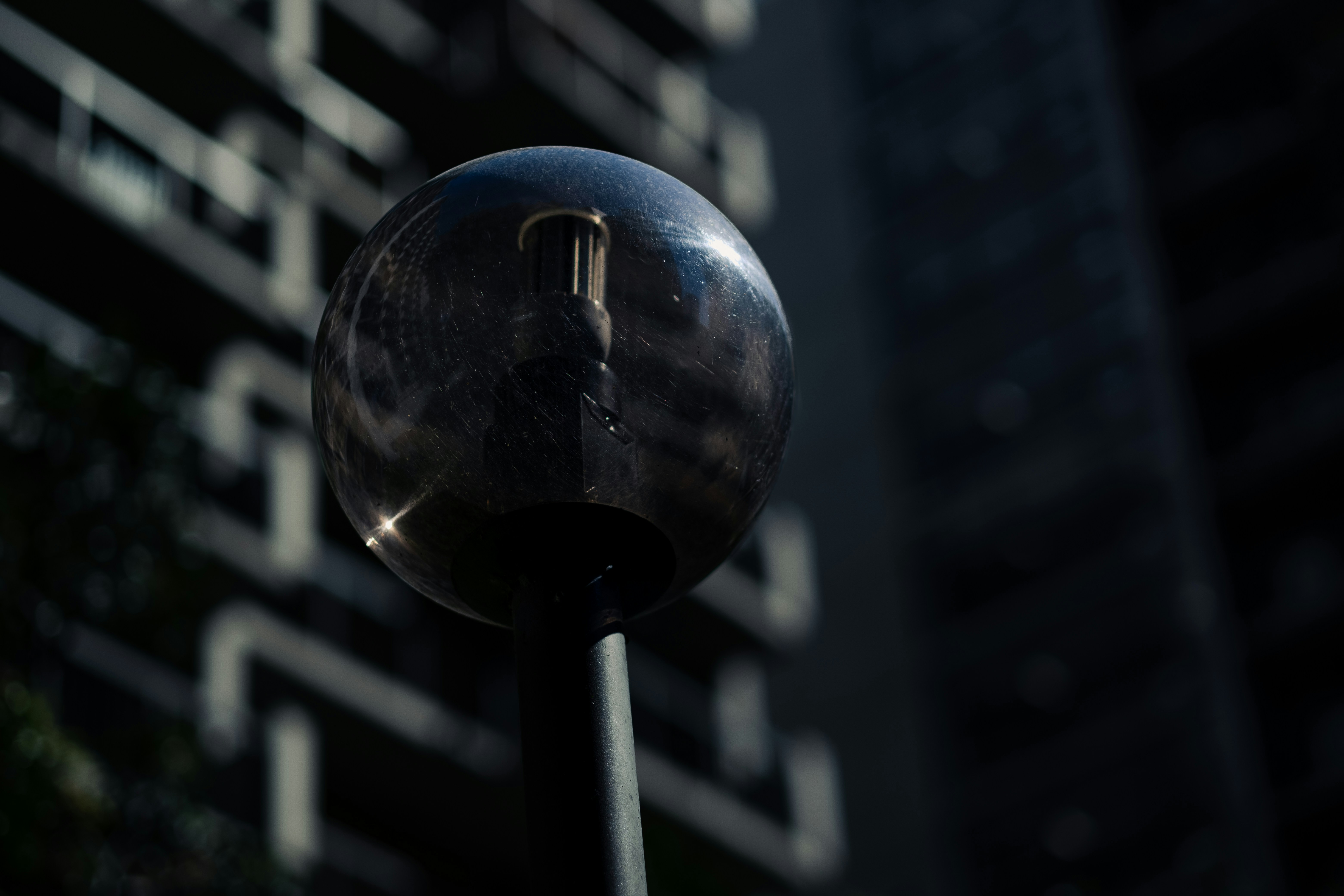 Urban Globe: A Weathered Lamp Post Against Modern Facades