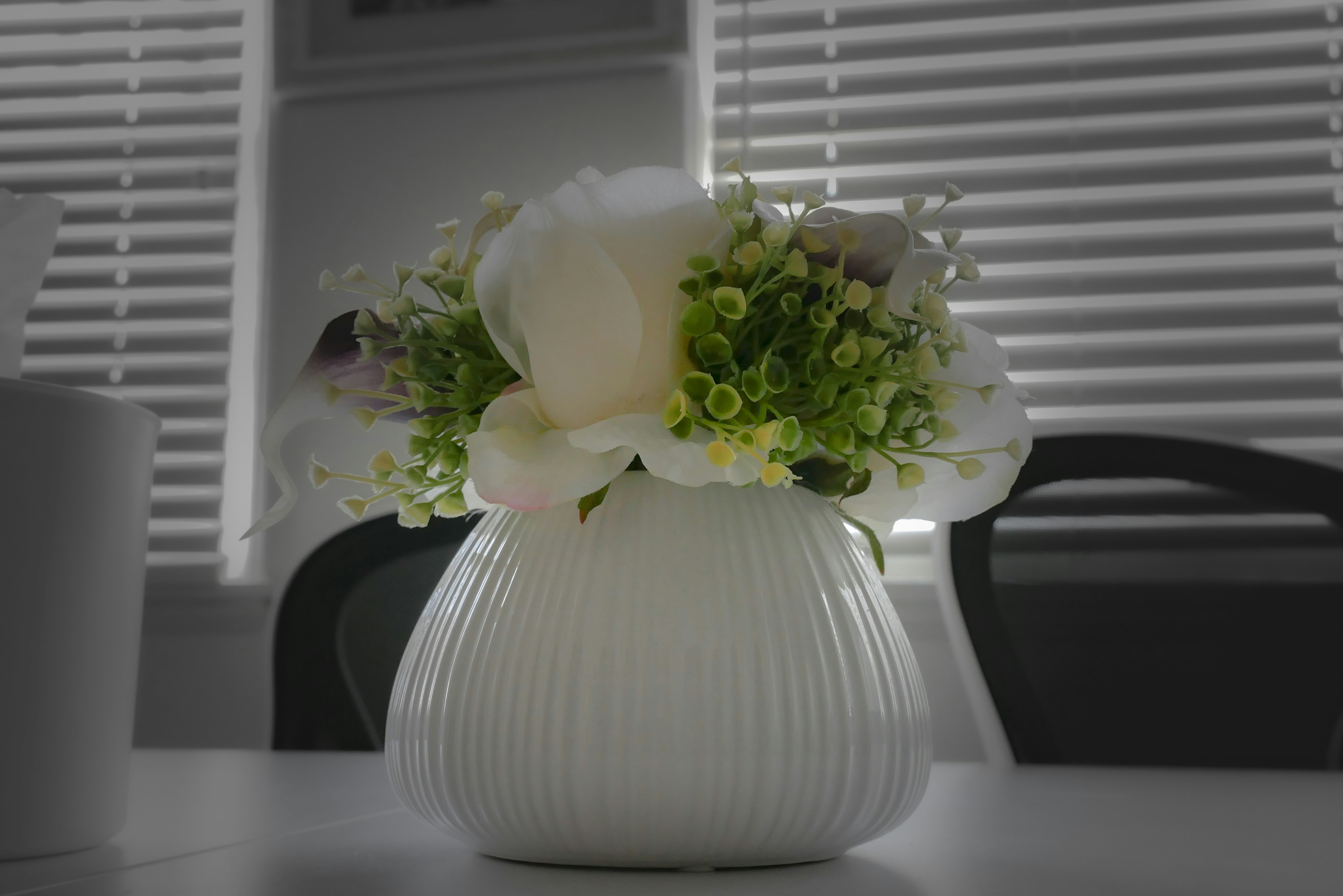 White ceramic vase with blooms on a sunlit conference table