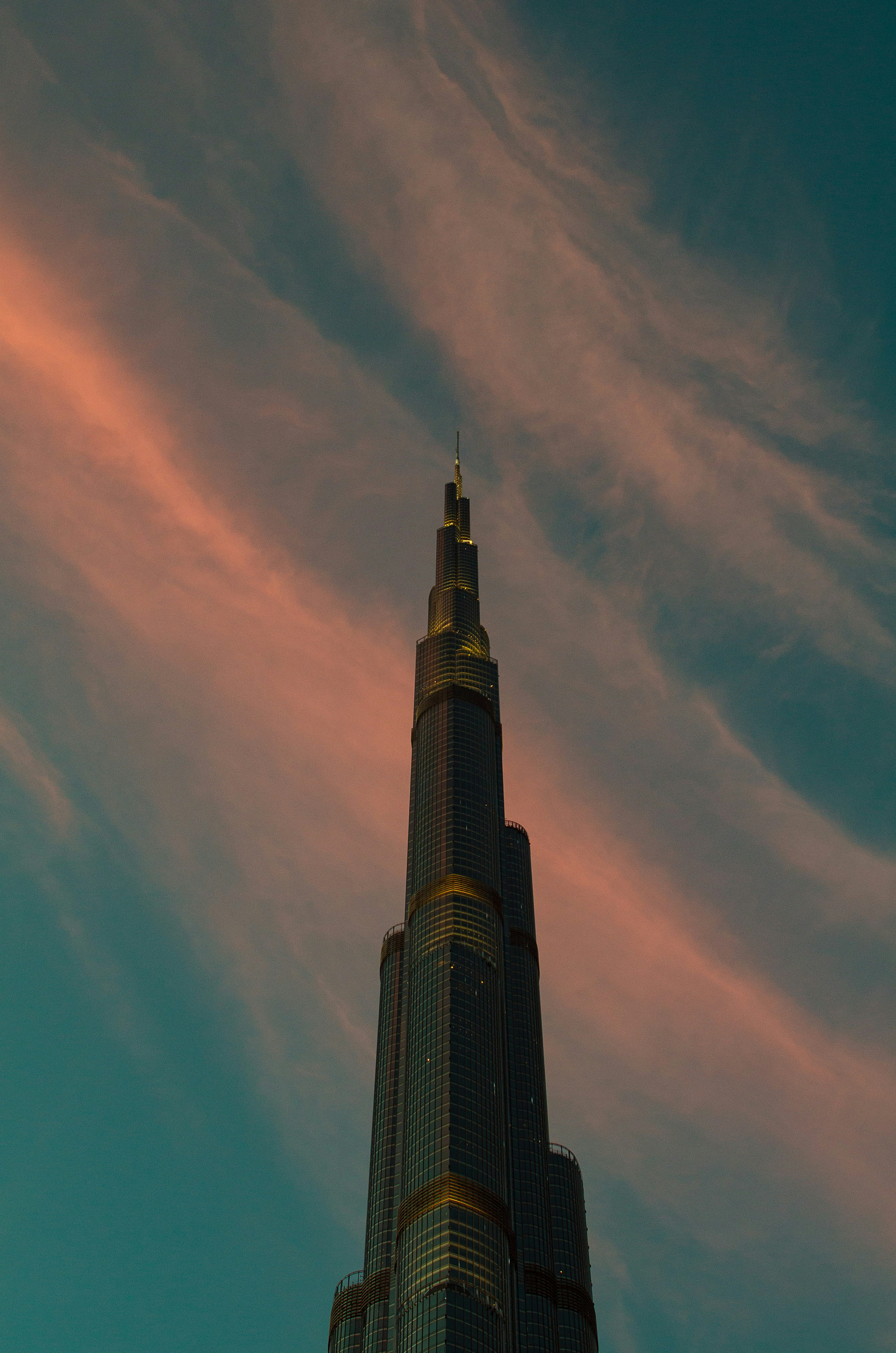 Burj Khalifa piercing the twilight sky, surrounded by wispy clouds painted in hues of pink and blue.