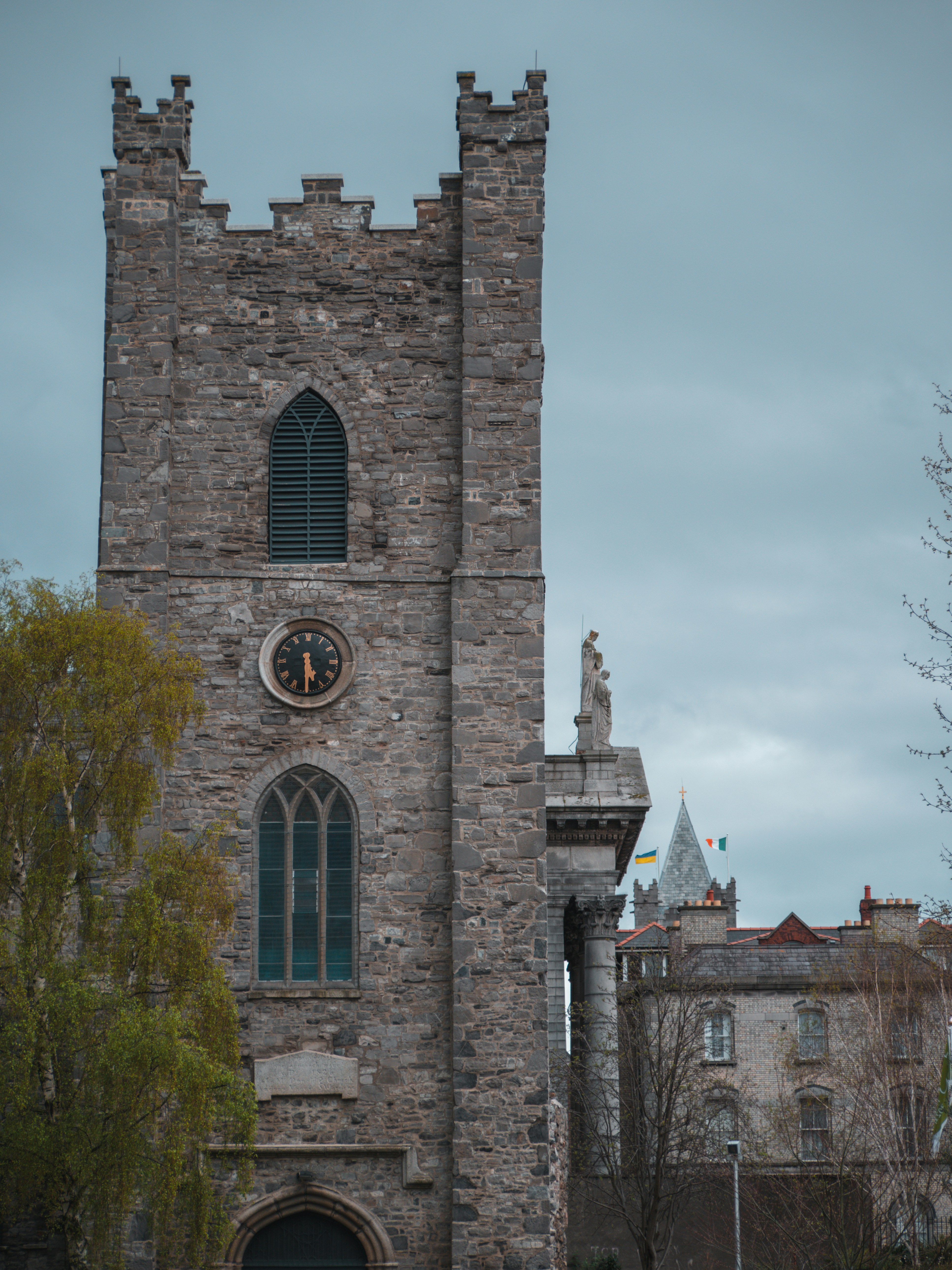 Historic stone tower featuring a clock and intricate architectural details against a cloudy sky.