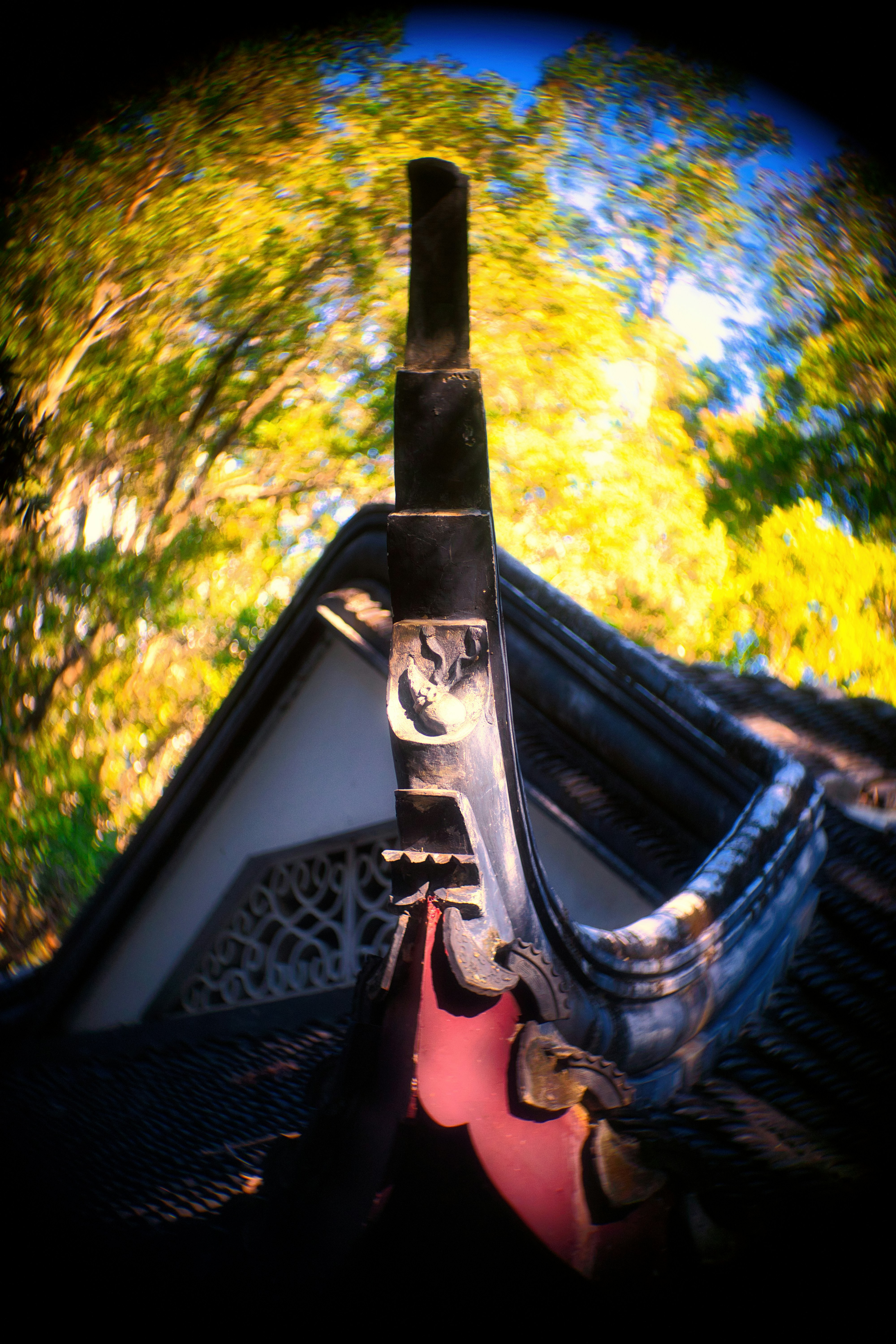 Intricate architectural detail of a traditional roof ornament against a backdrop of vibrant foliage.