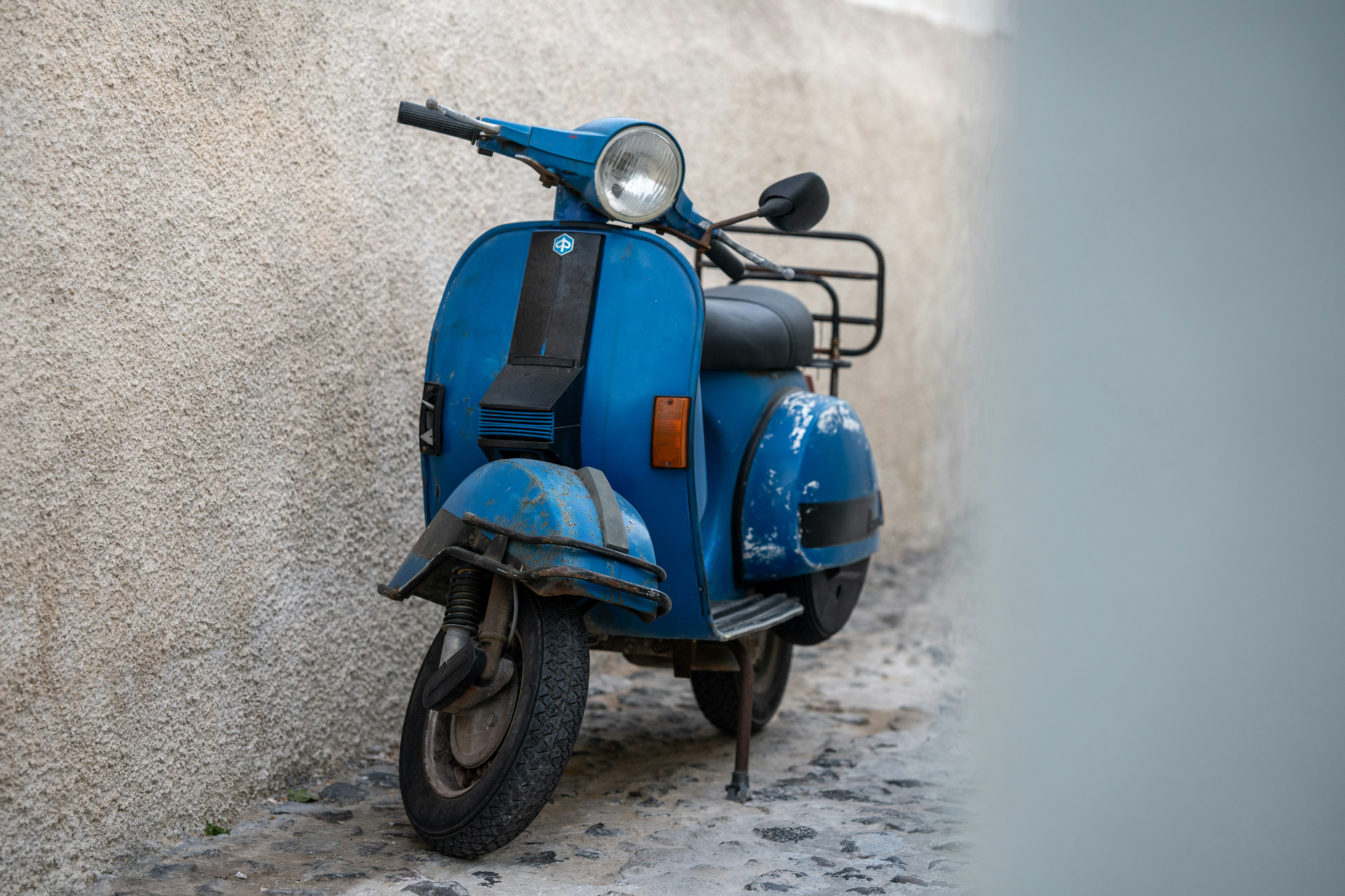 Foto zum Thema Ein blauer Motorroller parkt neben einer Wand ...