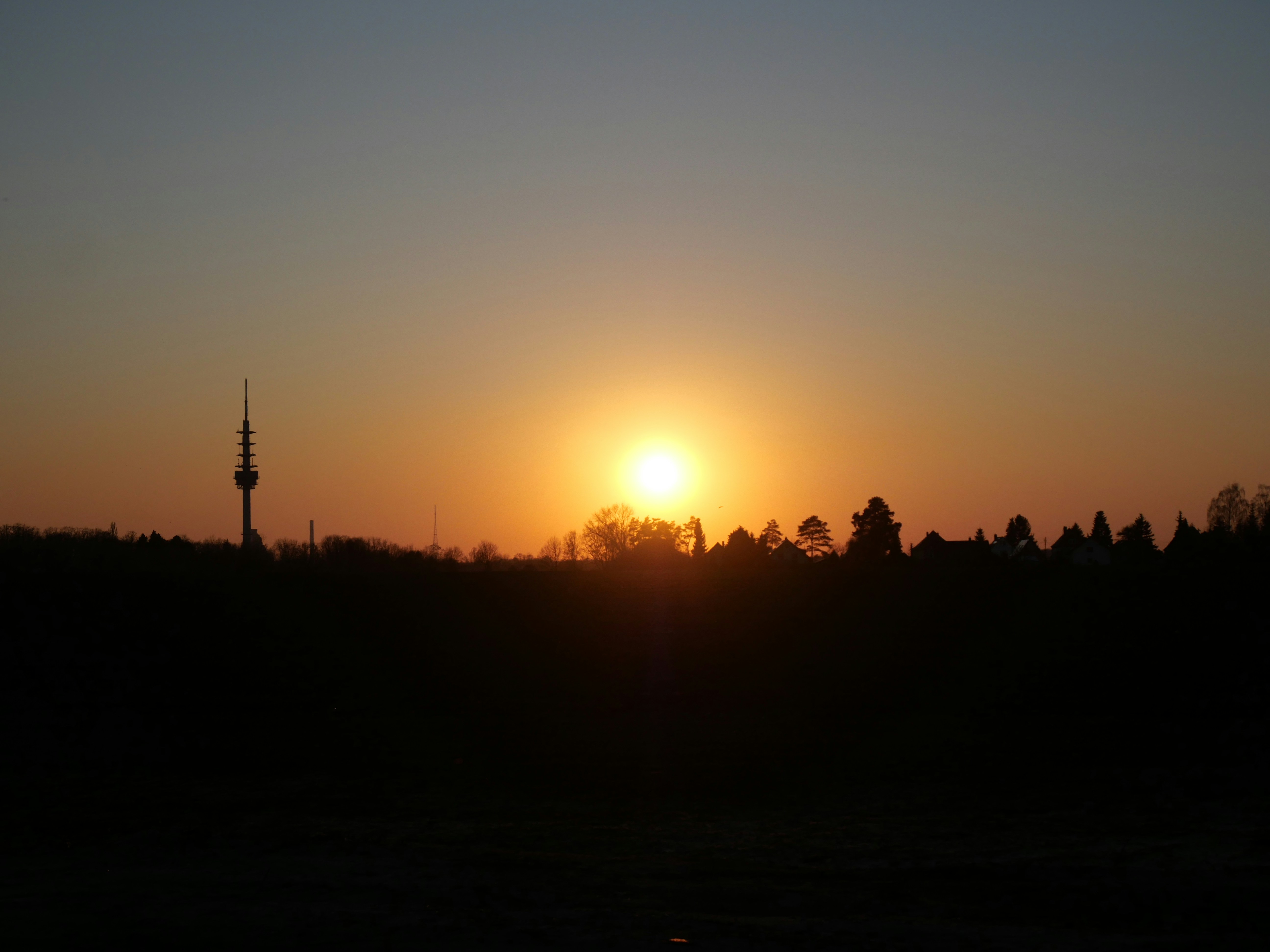 The sun is setting over a hill with a tower in the distance photo ...