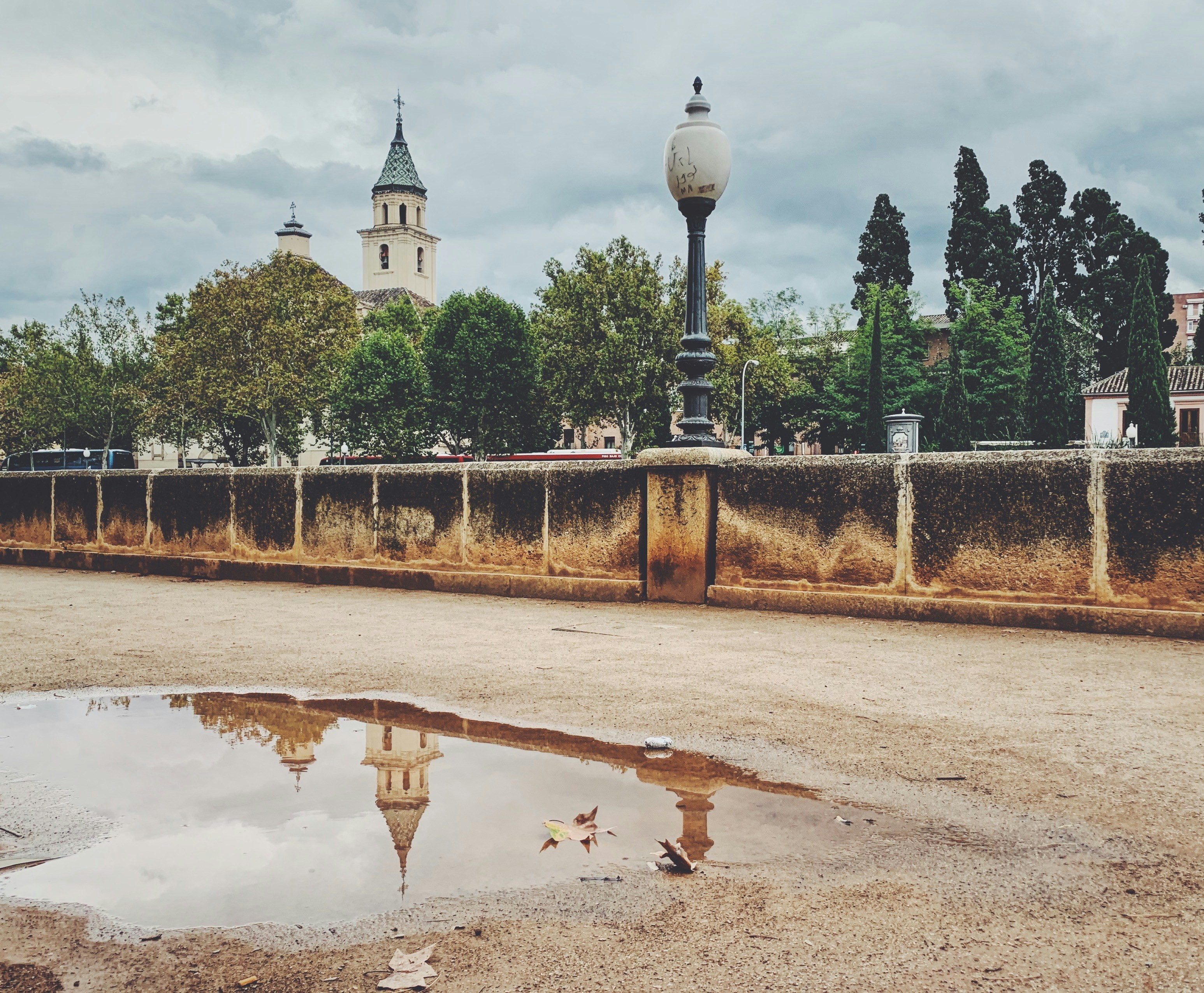 A reflection of a clock tower in a puddle of water photo – Free Granada ...