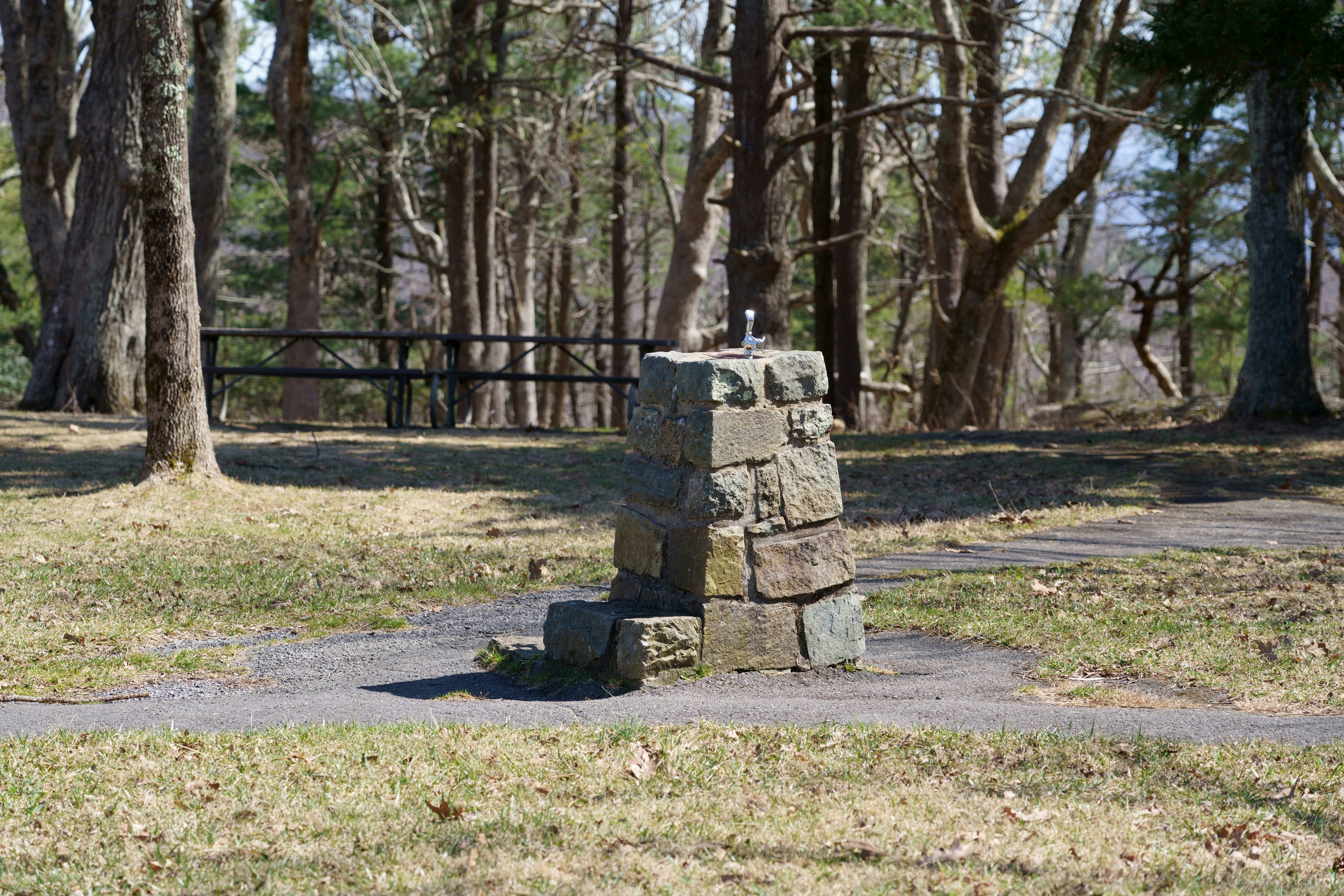 Cairn in a Quiet Park: Stacked Stones Mark a Calm, Sunlit Path