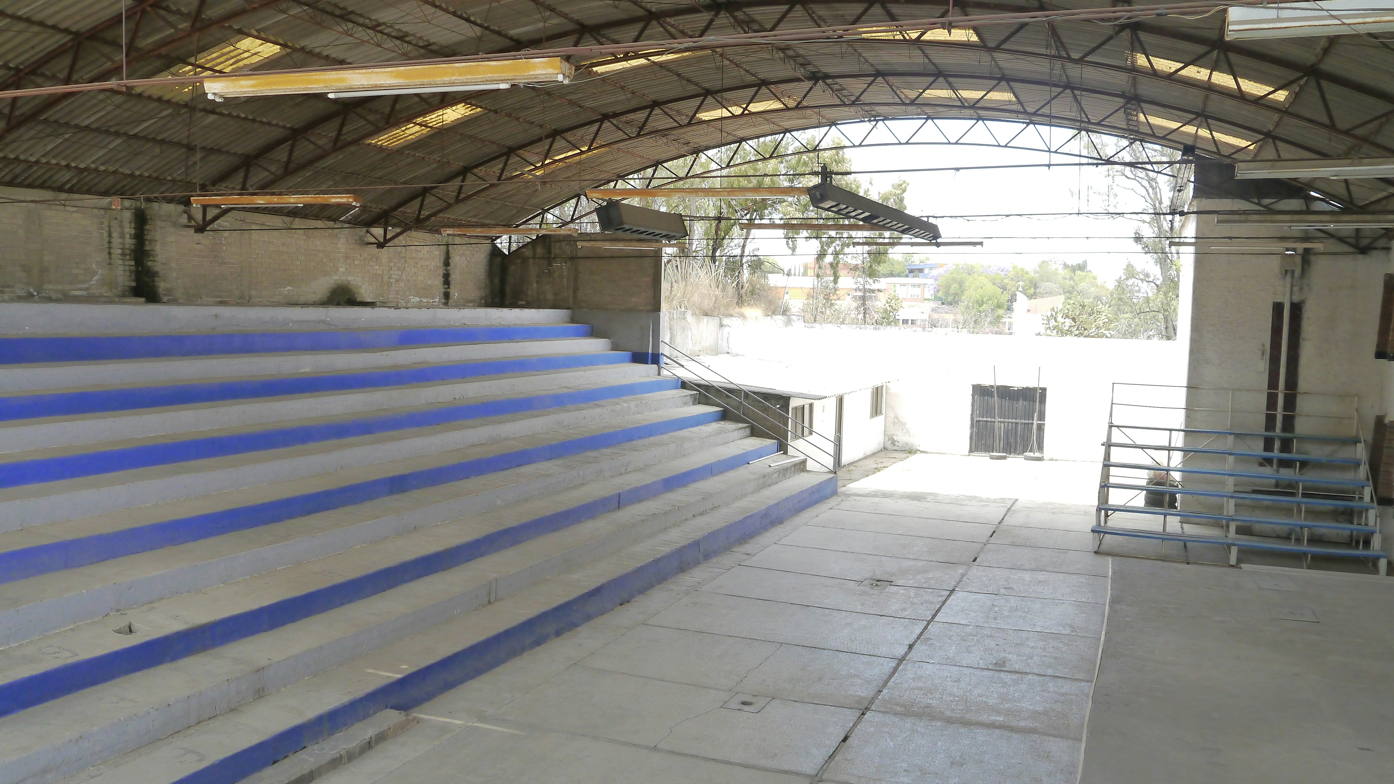 Empty bleachers with blue accents in a spacious indoor sports facility, highlighting the contrast between structure and absence of activity.