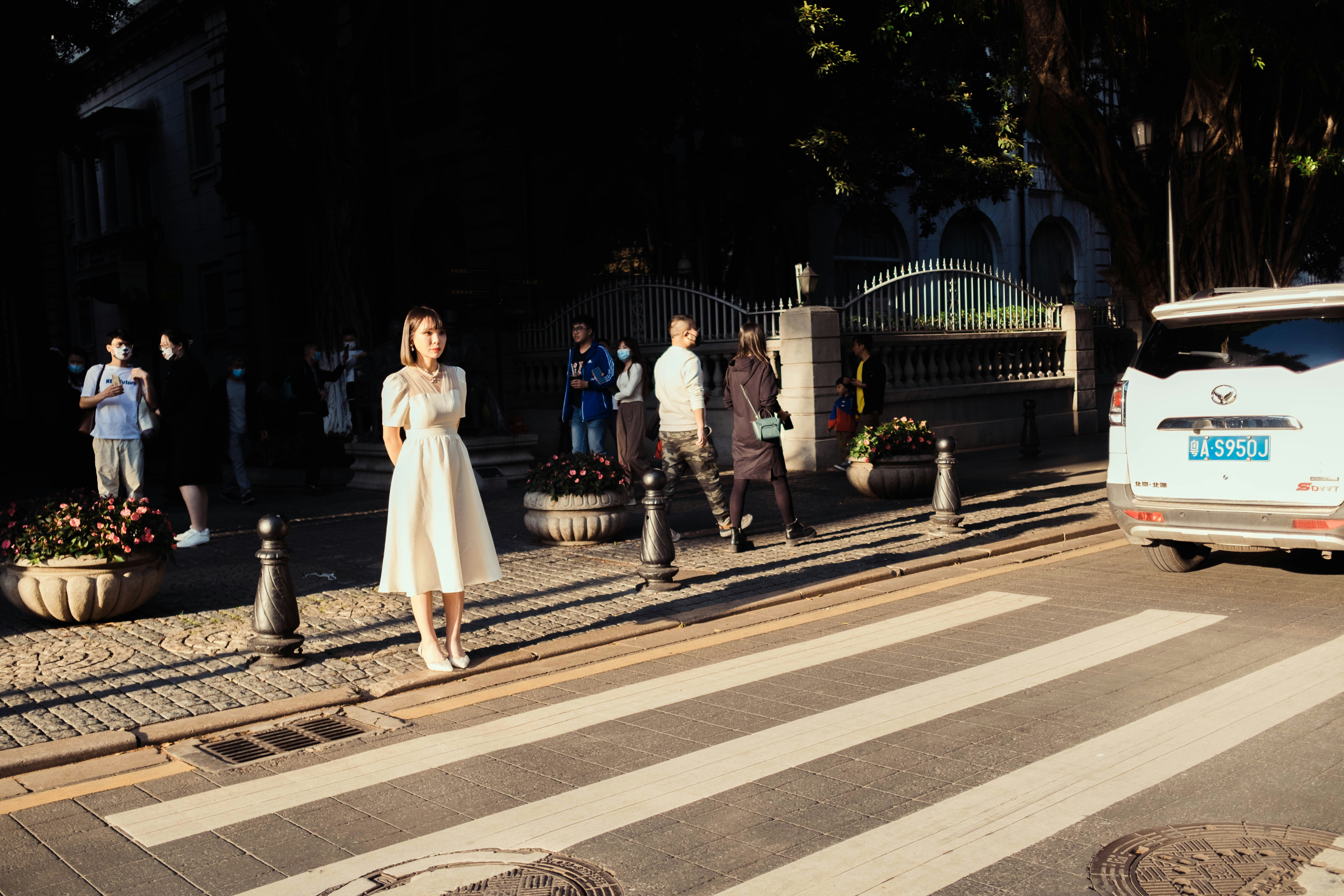 A woman in a white dress standing on a street corner photo – Free ...