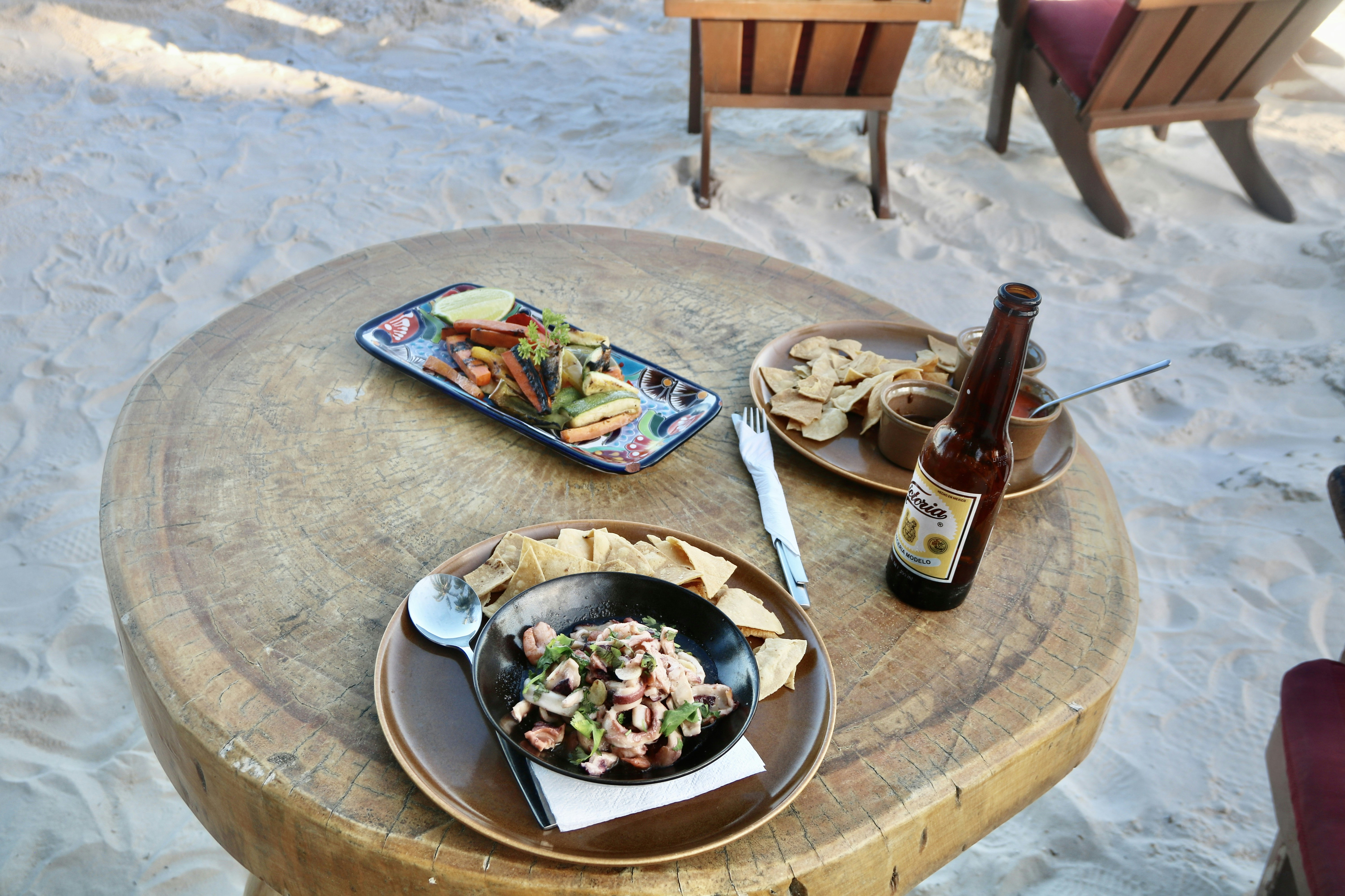 Round Beach Table Feast: Pan-Dish, Chips, and a Beer Under Sun