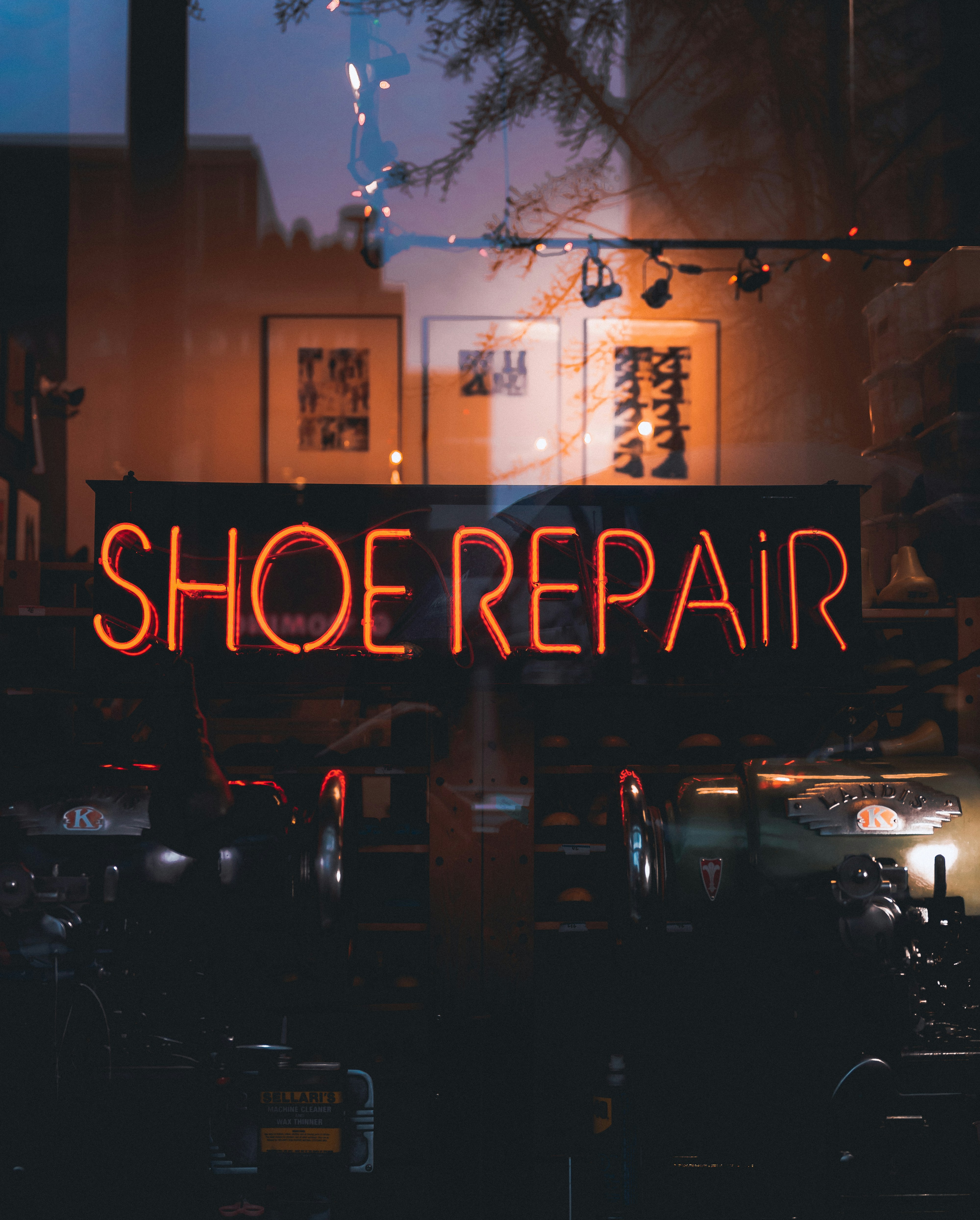 a neon shoe repair sign in a store window