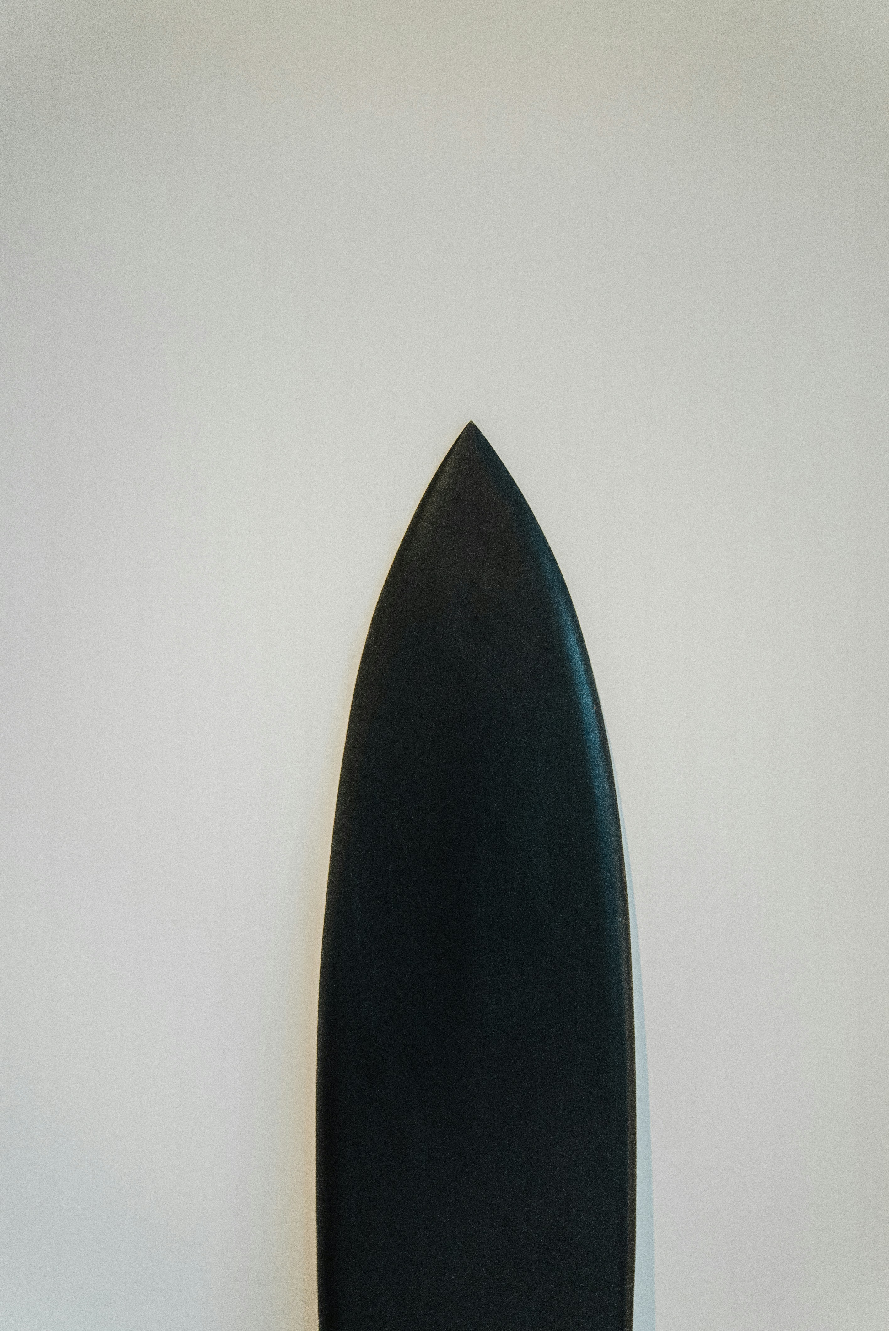 A black surfboard leaning up against a white wall photo – Free Inetrior ...