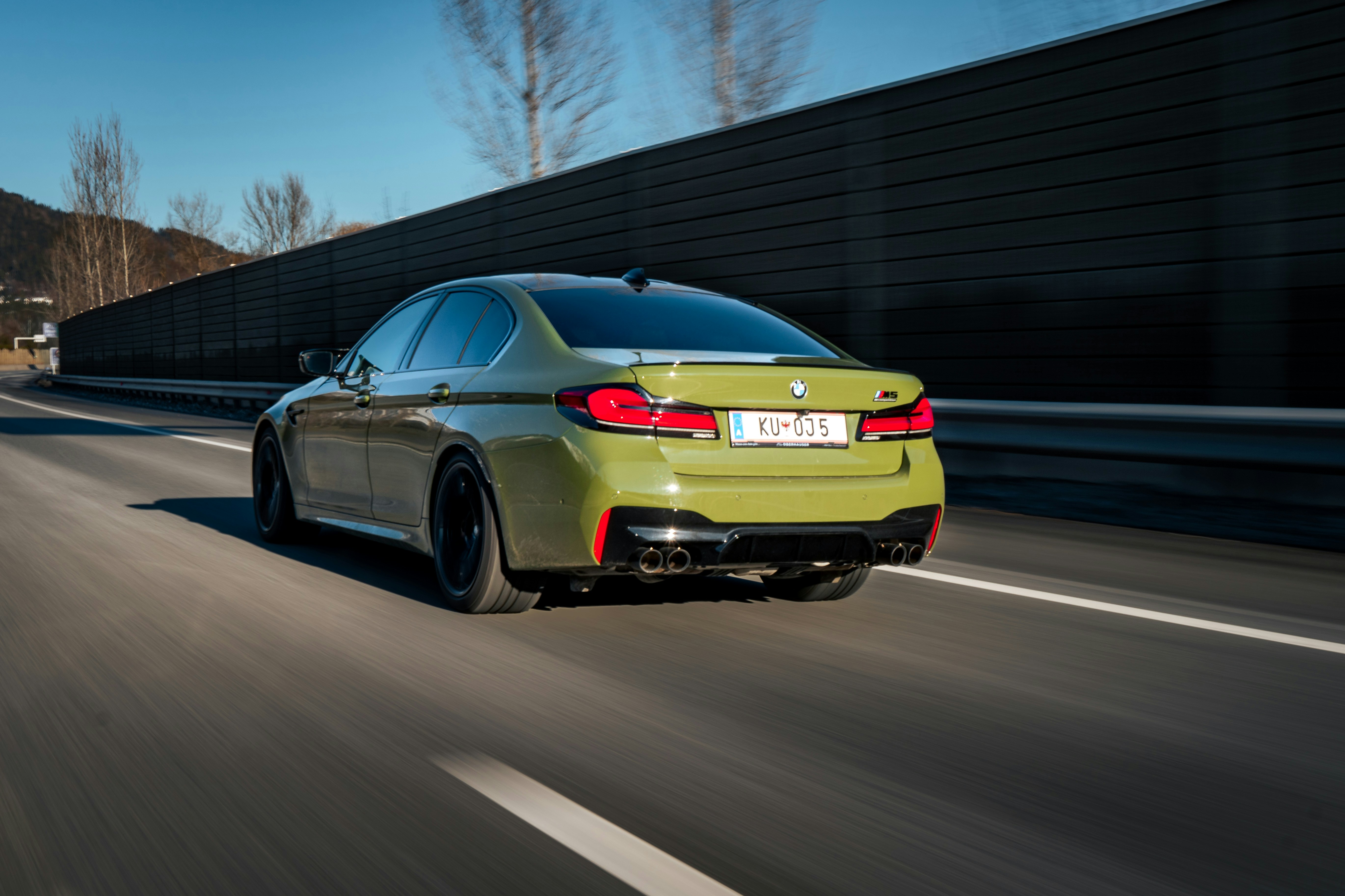 A green car driving down a road next to a wall photo – Free Tyrol Image ...