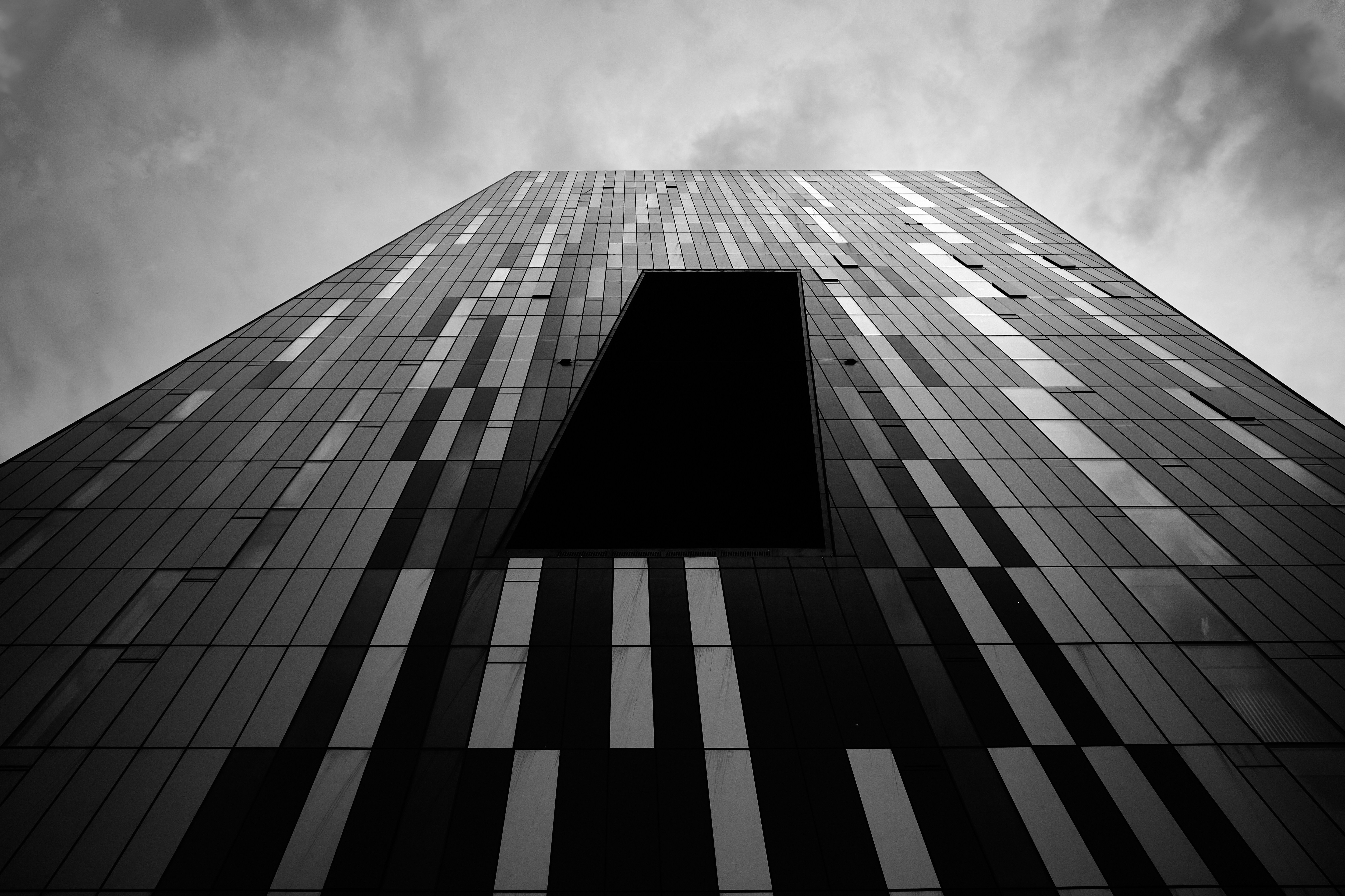 Abstract architectural view of a towering building with a prominent void, showcasing a striking interplay of dark and light surfaces.