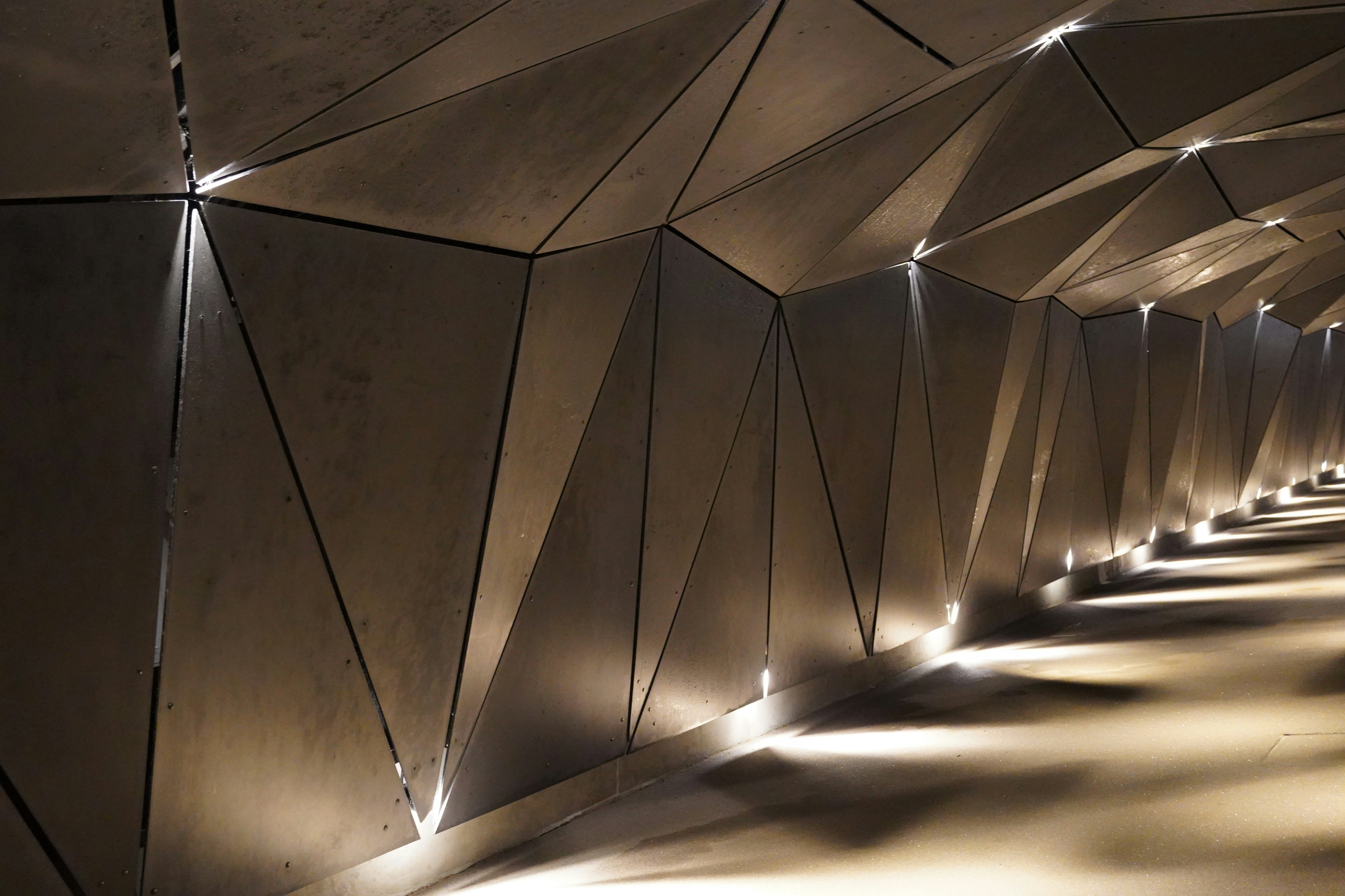 Dimly lit corridor with angular, geometric wall panels creating a futuristic ambiance.