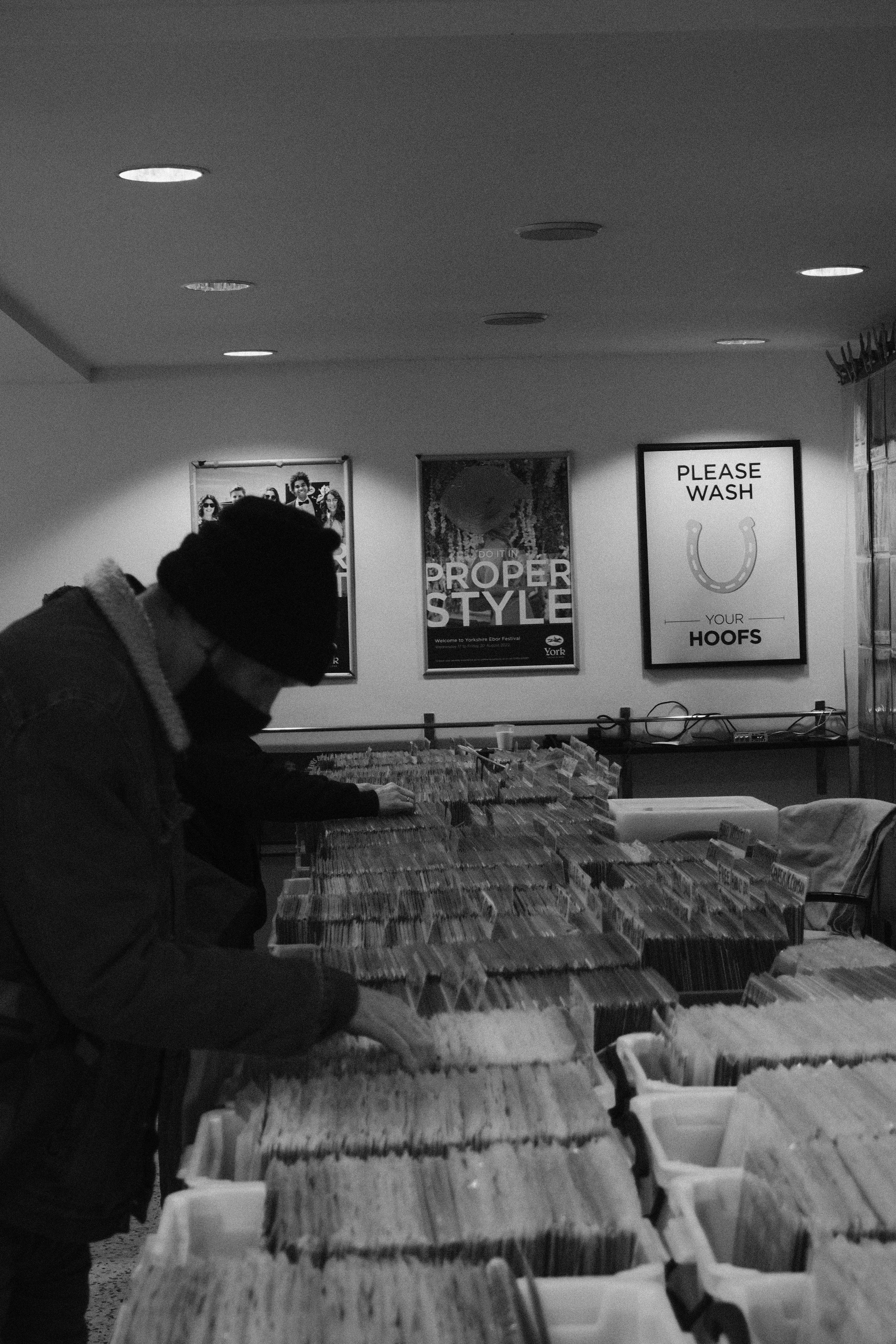 Quiet Aisle, Loud Texture: Hands Weighing the LPs in a Dim Record Shop
