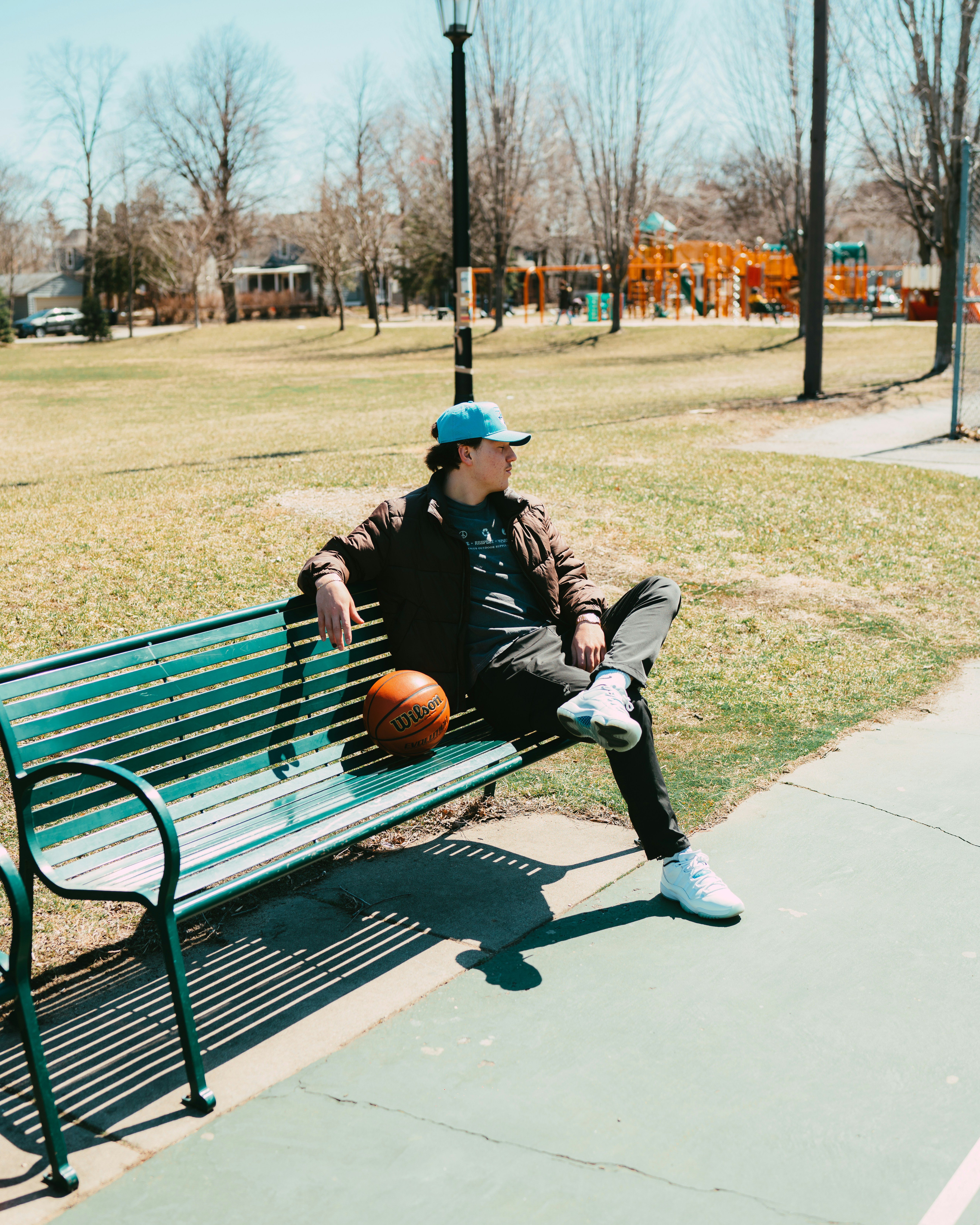 Sunlit Quiet: A Solo Moment with a Basketball on the Park Bench