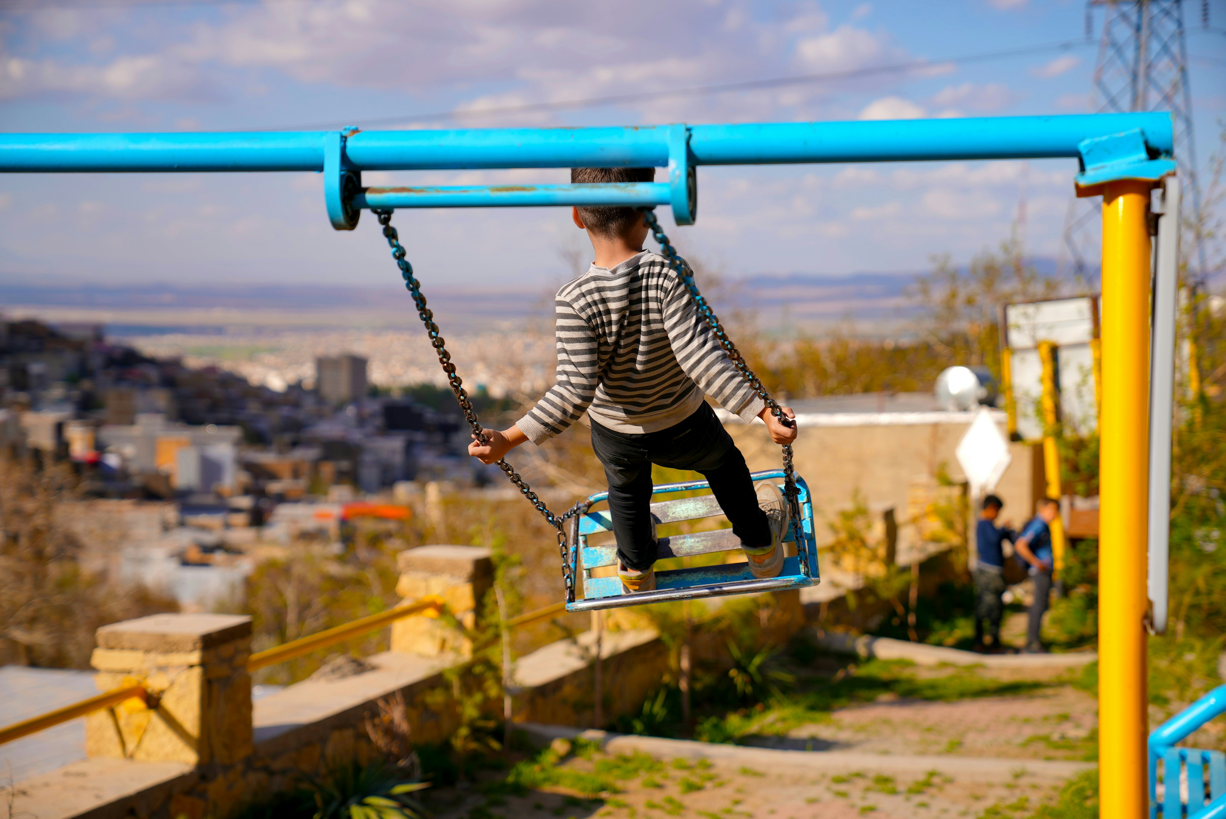 Swinging Against a Sunlit Cliffside: A Child's Playground with a Grand View