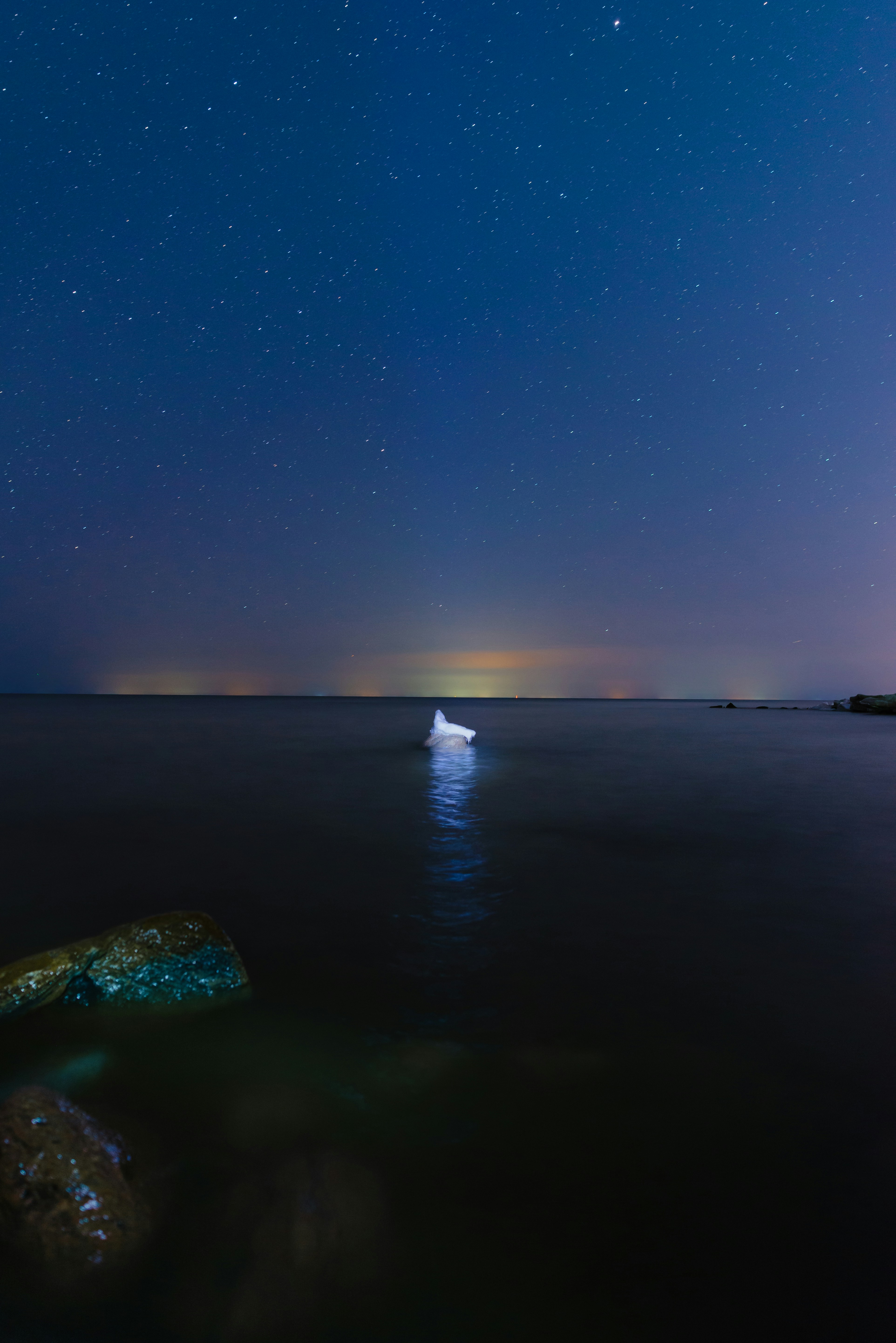 Ice Gem on a Velvet Sea: A Starry Night Over Calm Waters