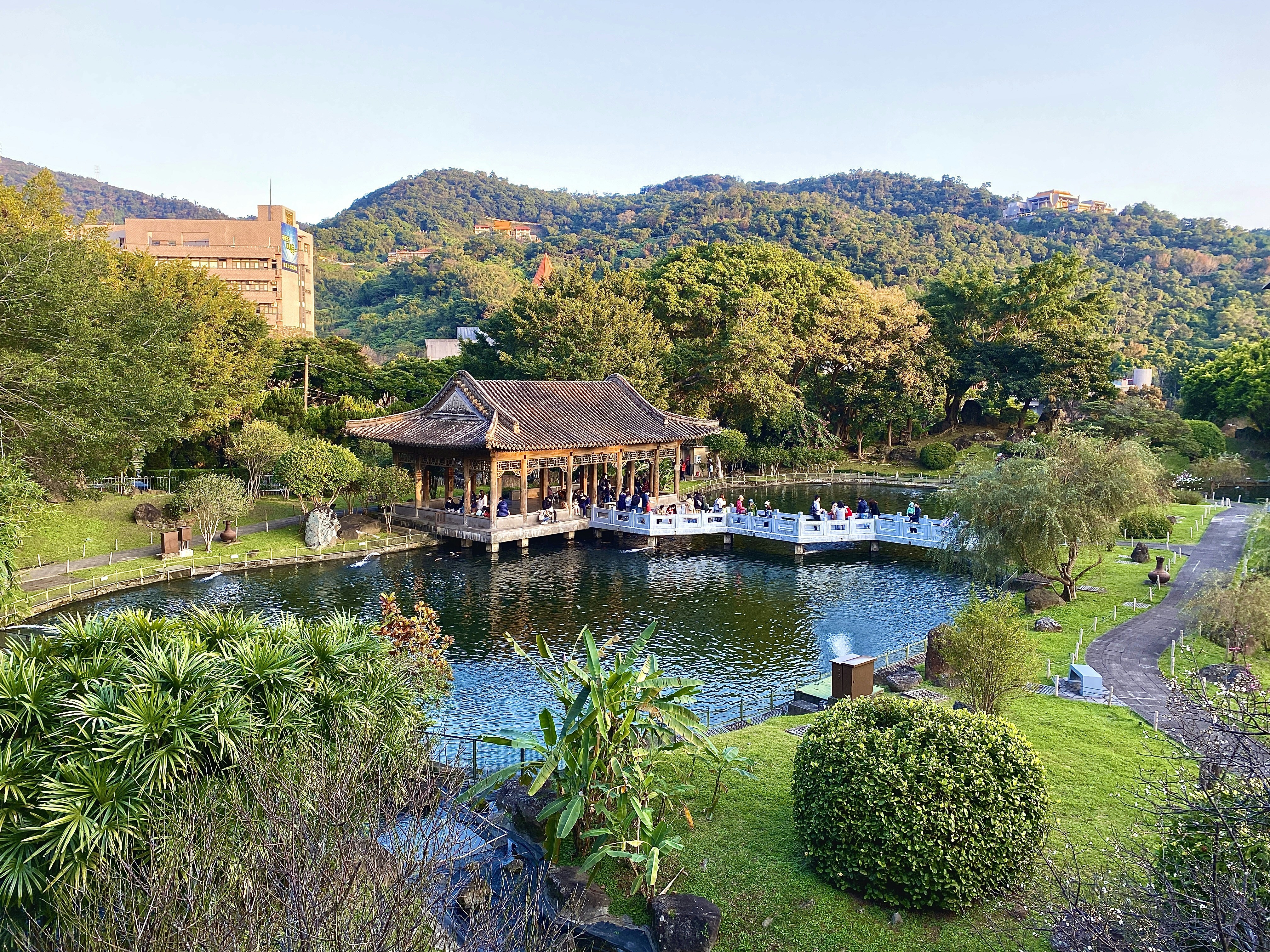 A lake surrounded by lush green trees and a pavilion photo – Free ...