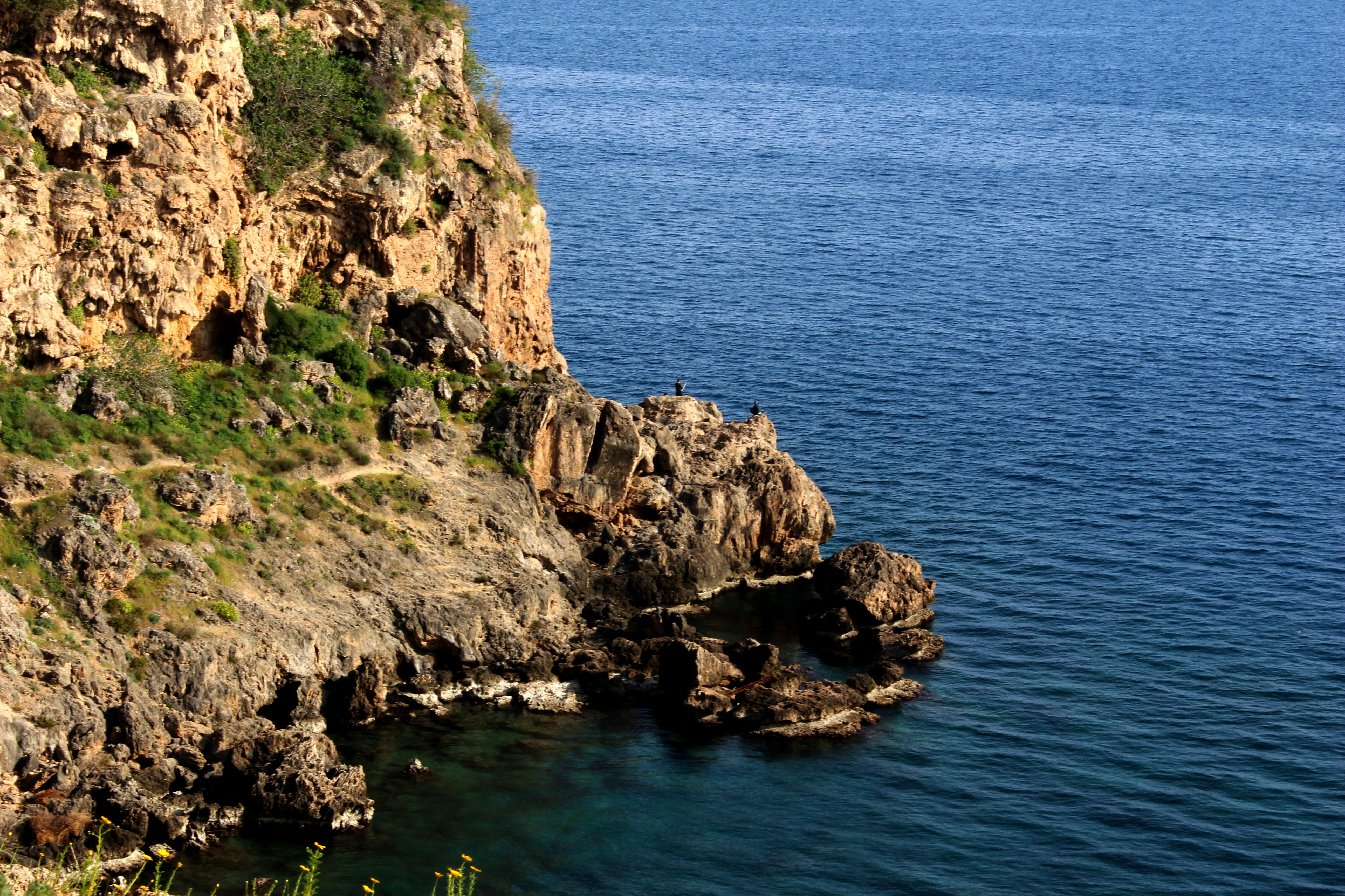 A rocky cliff on the edge of a body of water photo – Free Antalya Image ...