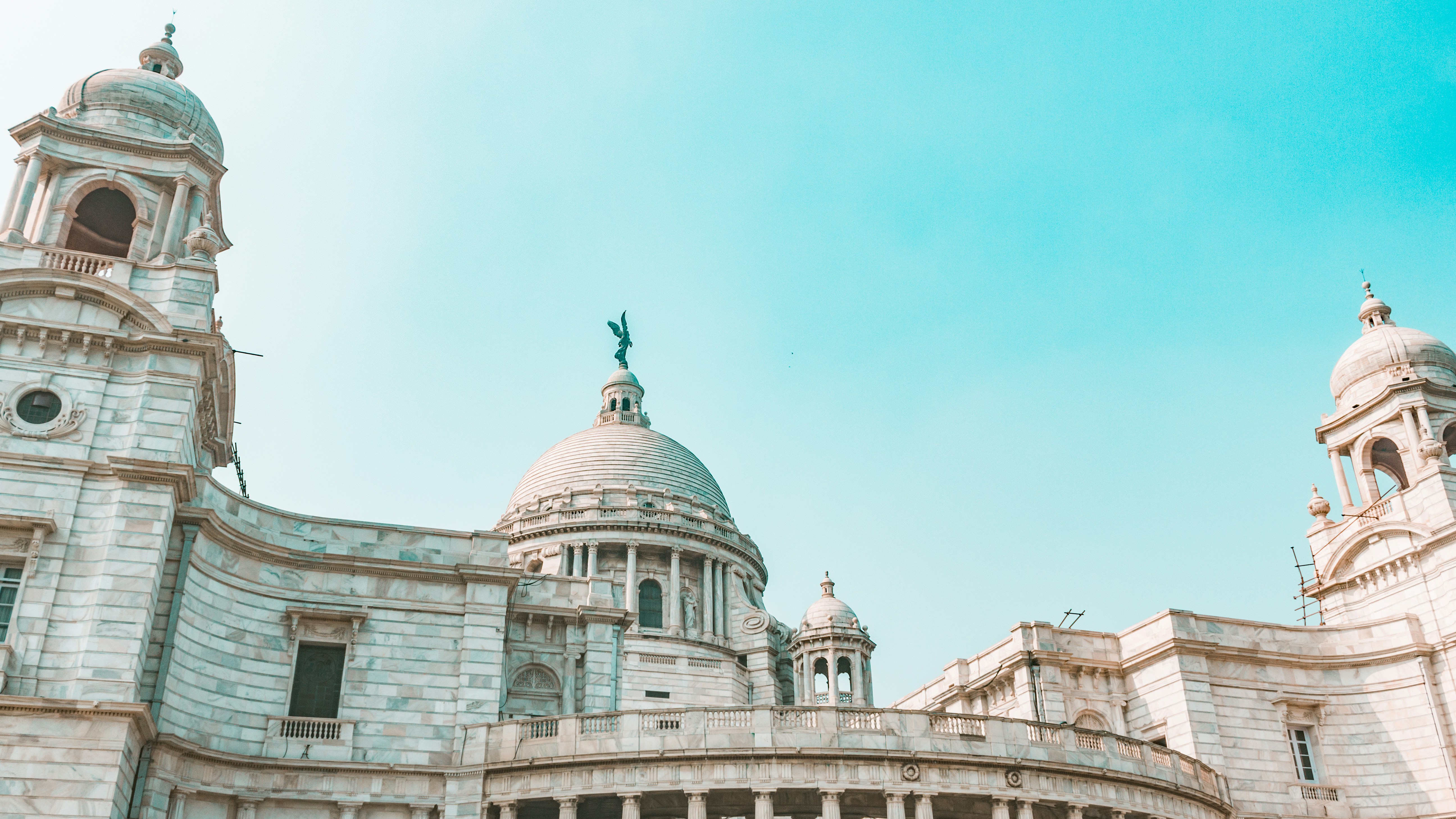 Elaborate historical building featuring grand domes and intricate details against a bright blue sky.