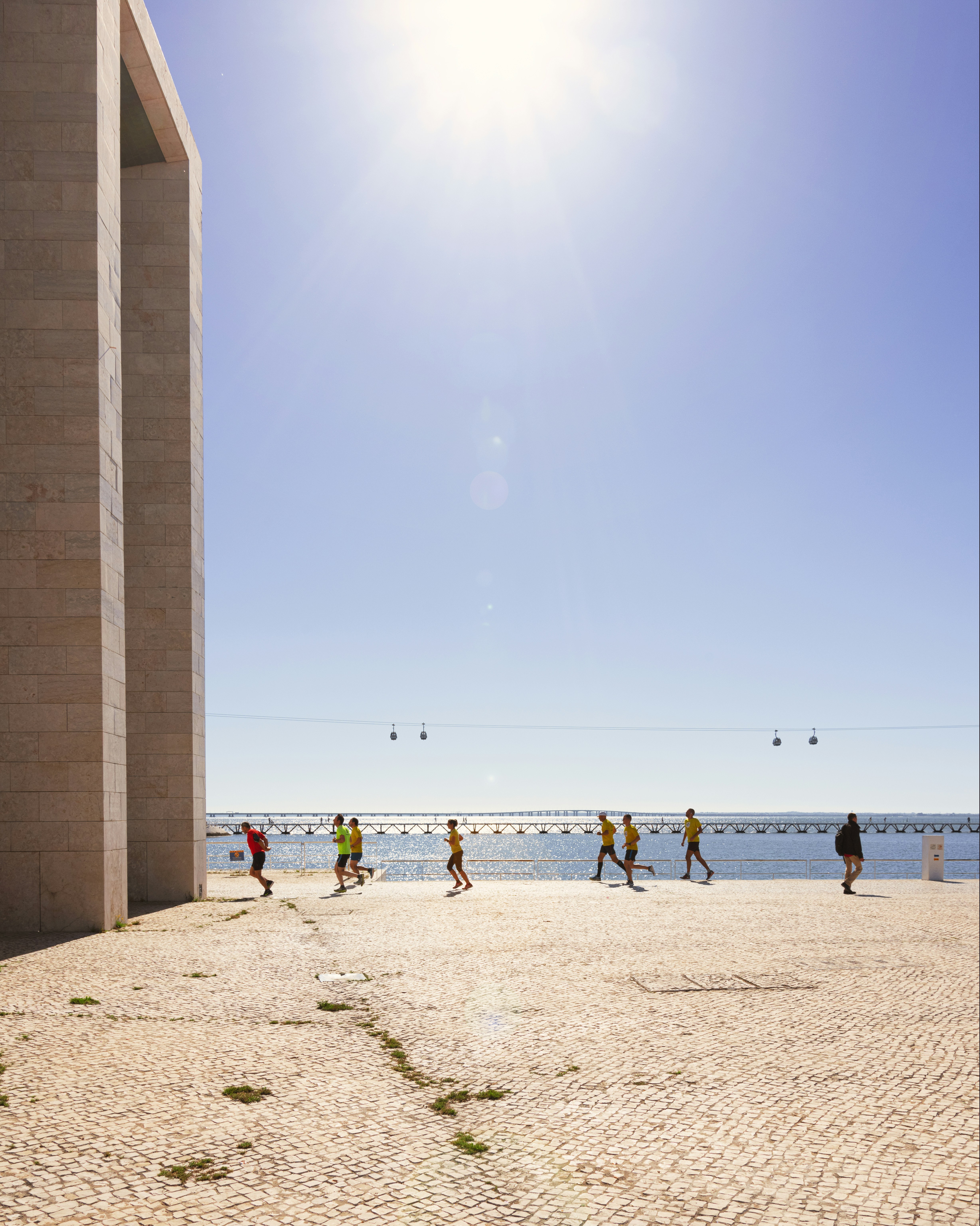 Sunlit Promenade: Runners Align the Seaside Horizon