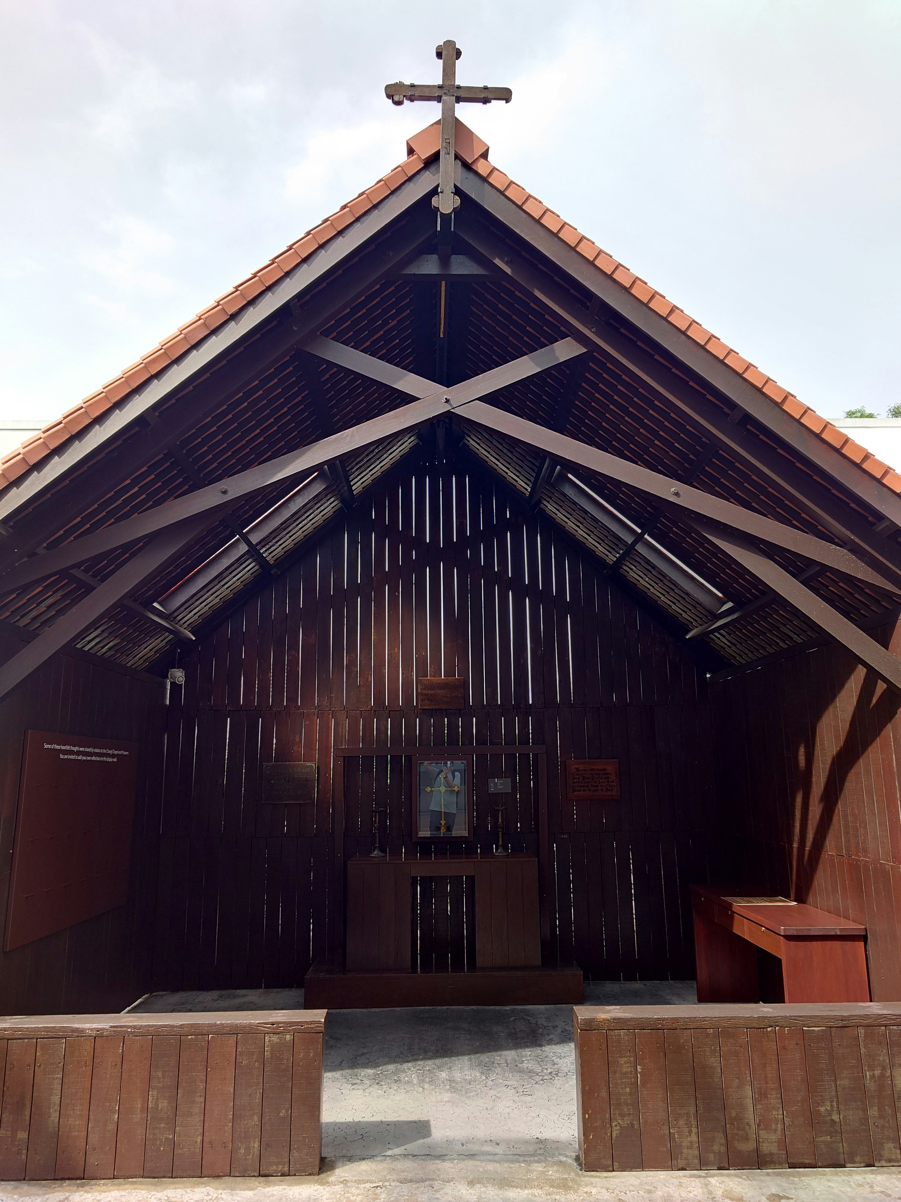 Interior view of a wooden chapel featuring a central altar and decorative cross overhead. The warm tones of the wood enhance the tranquil atmosphere.