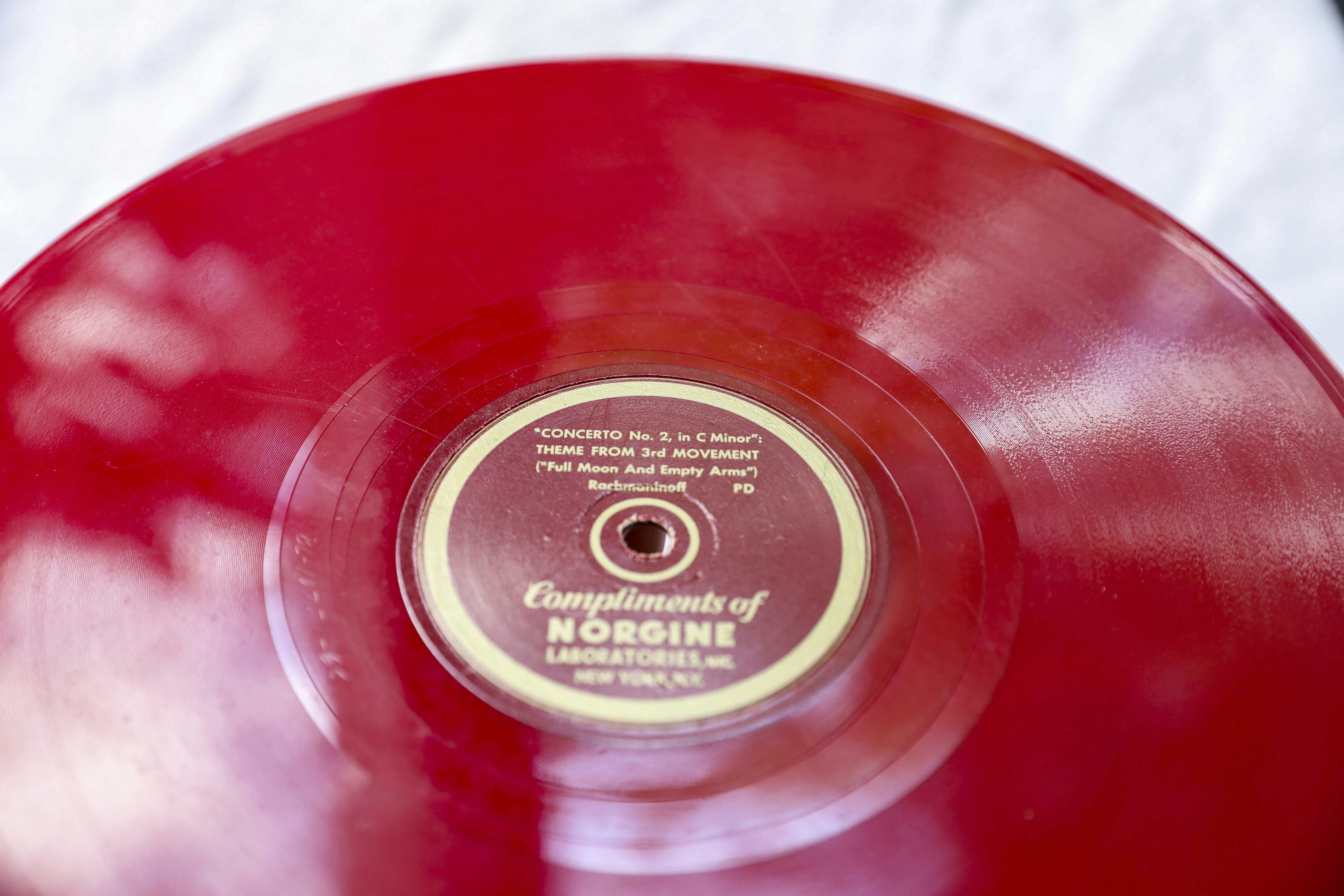 A close-up of a vibrant red vinyl record showcasing intricate label details. The texture and color evoke a sense of musical history.