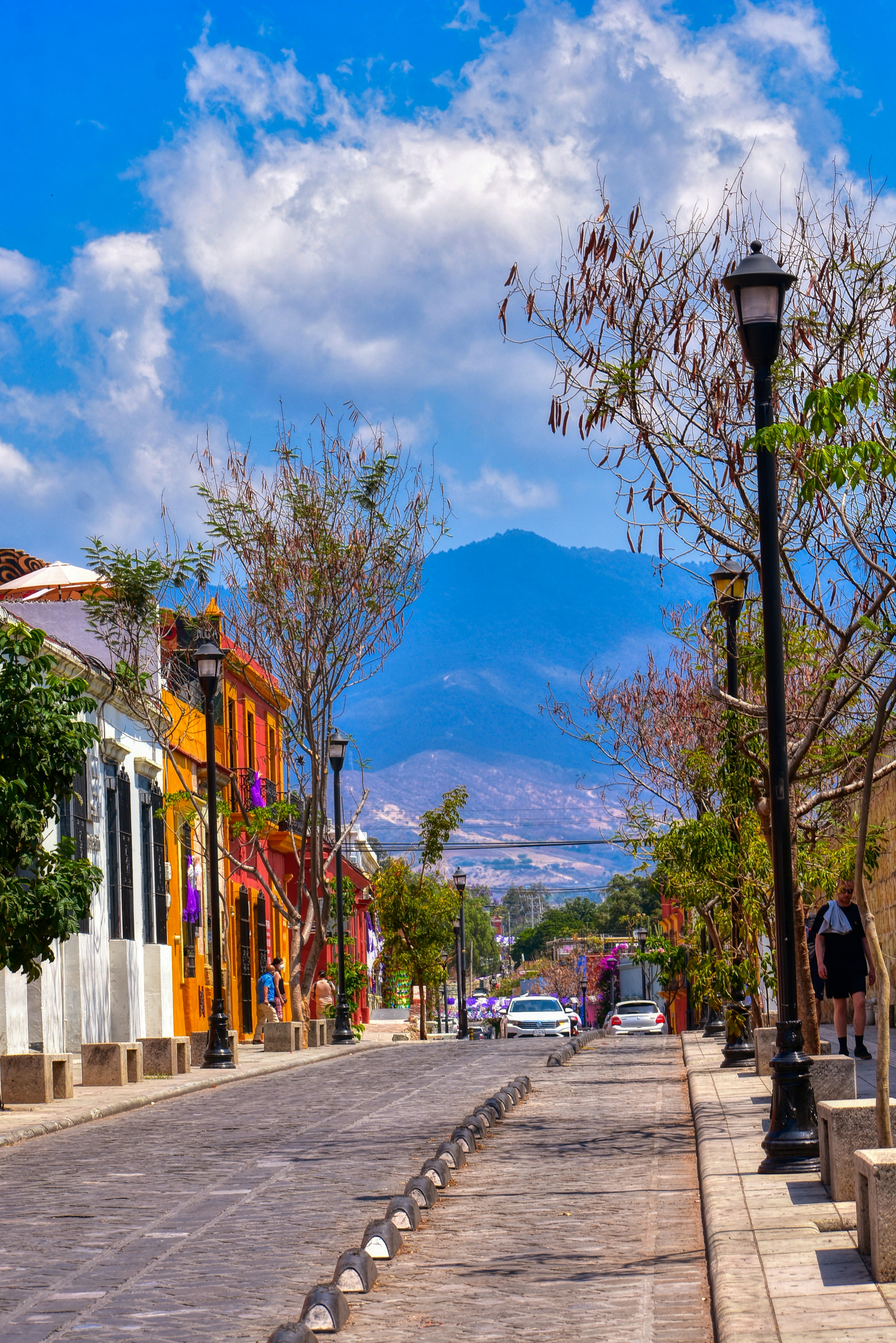 Colorful city street with bright buildings and a distant mountain under a blue sky.