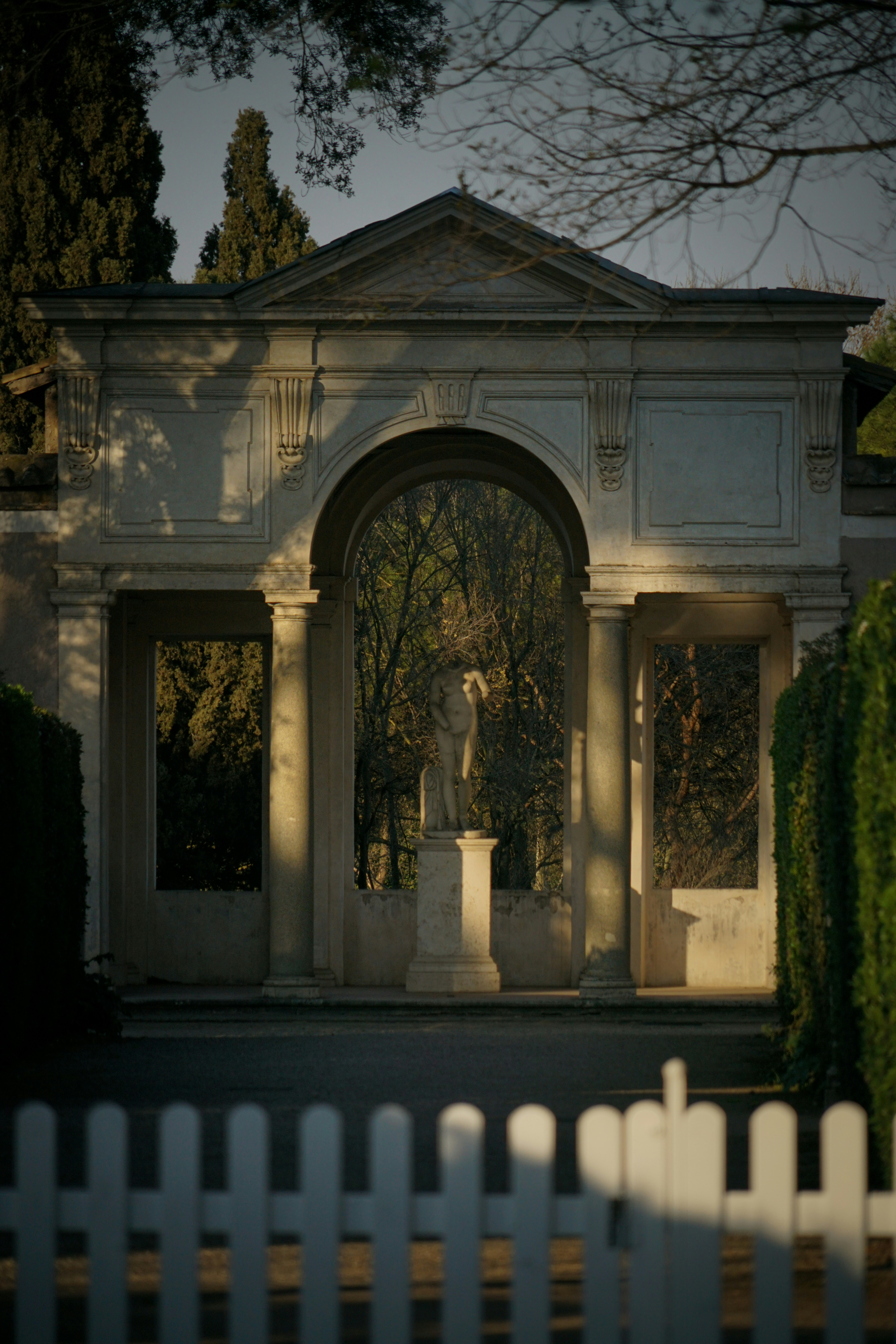 Dawn Between Pillars: A statue framed by a classical arch