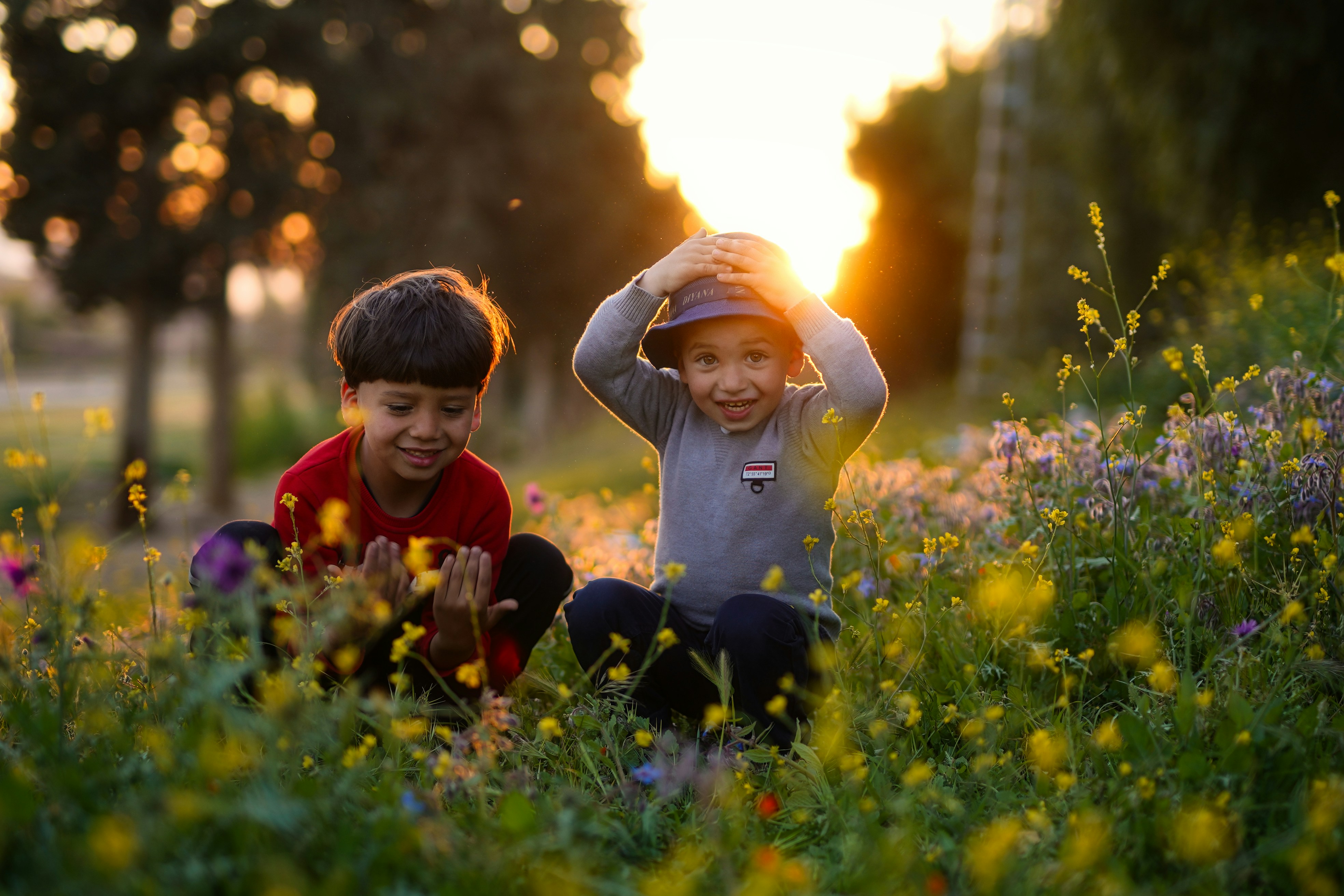 Two children playing in a vibrant field of wildflowers during sunset, capturing the essence of childhood joy and exploration.
