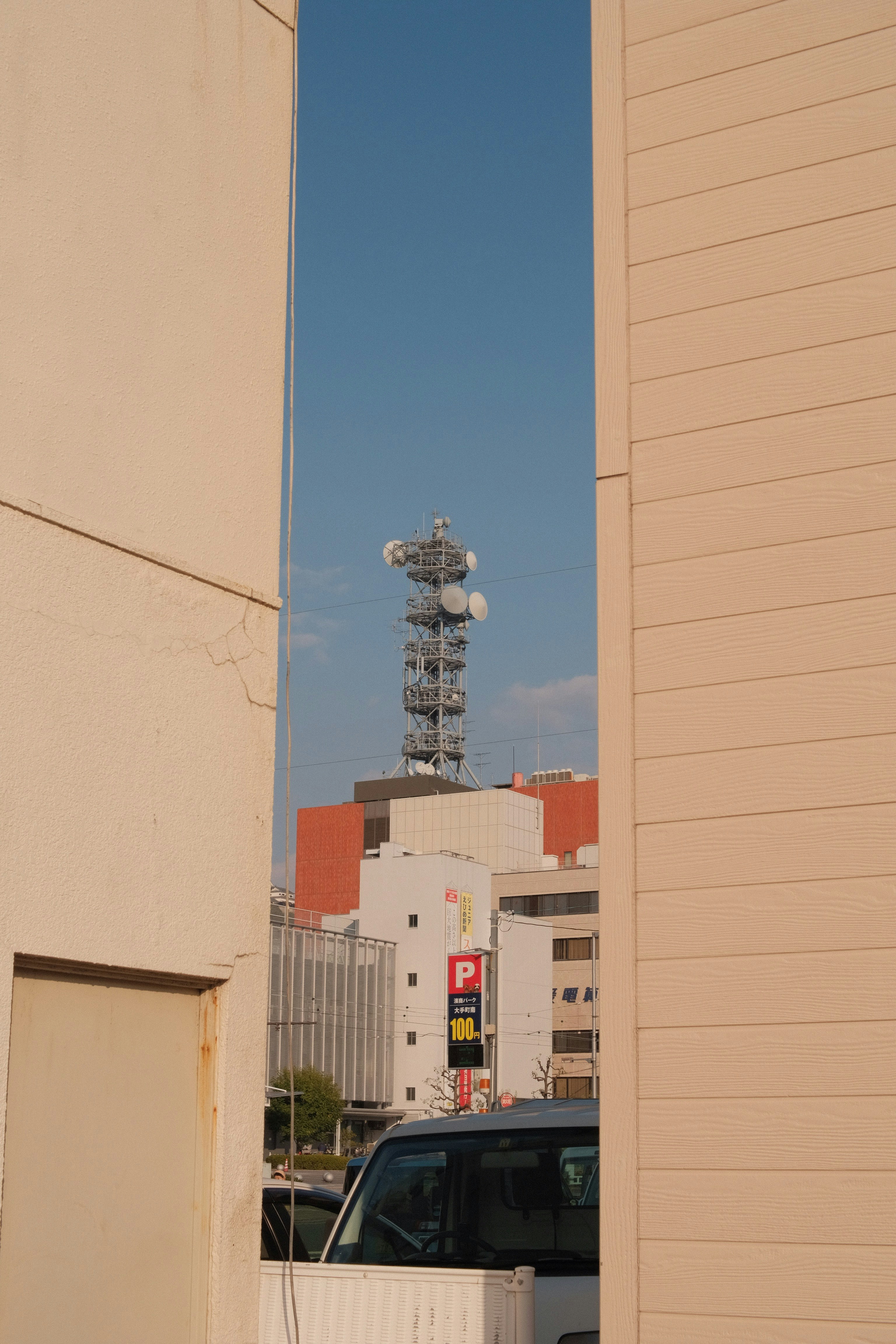 Telecommunication tower framed by two buildings in an urban setting, showcasing the blend of architecture and technology. 