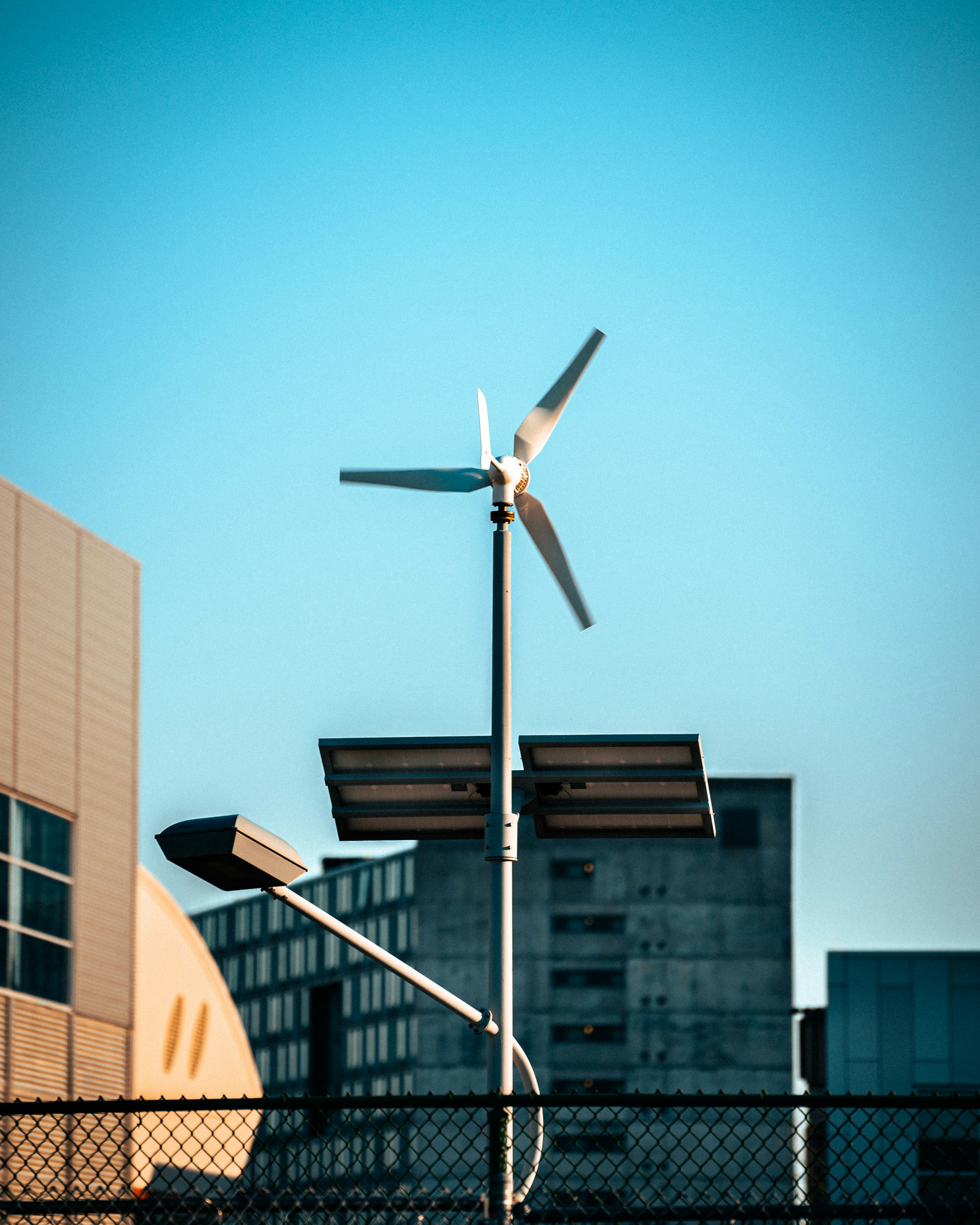 Urban Windmill Rising Over the Fence Against a Clear Azure Sky