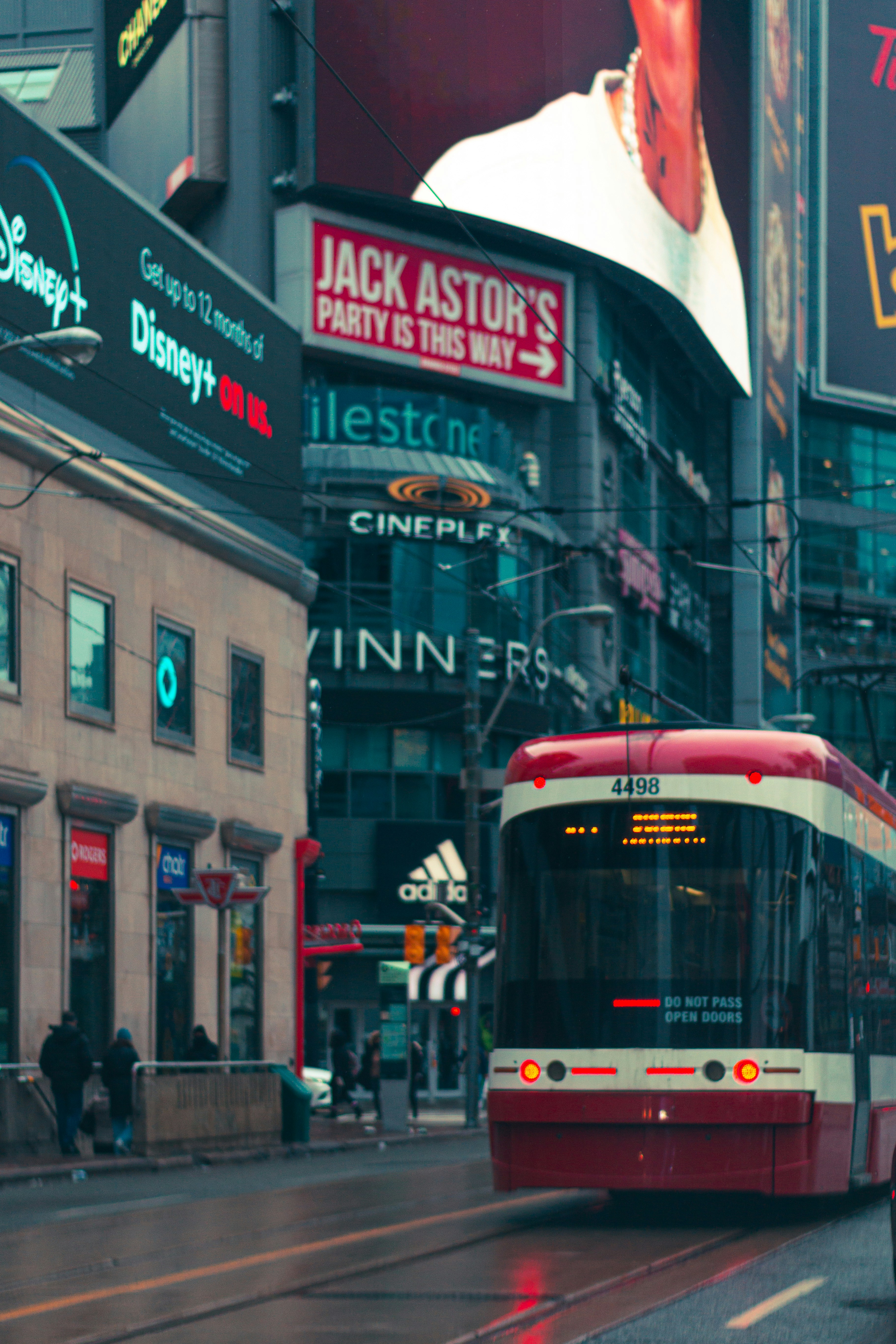 Crimson Streetcar Cuts Through a Neon-Lined Cityscape