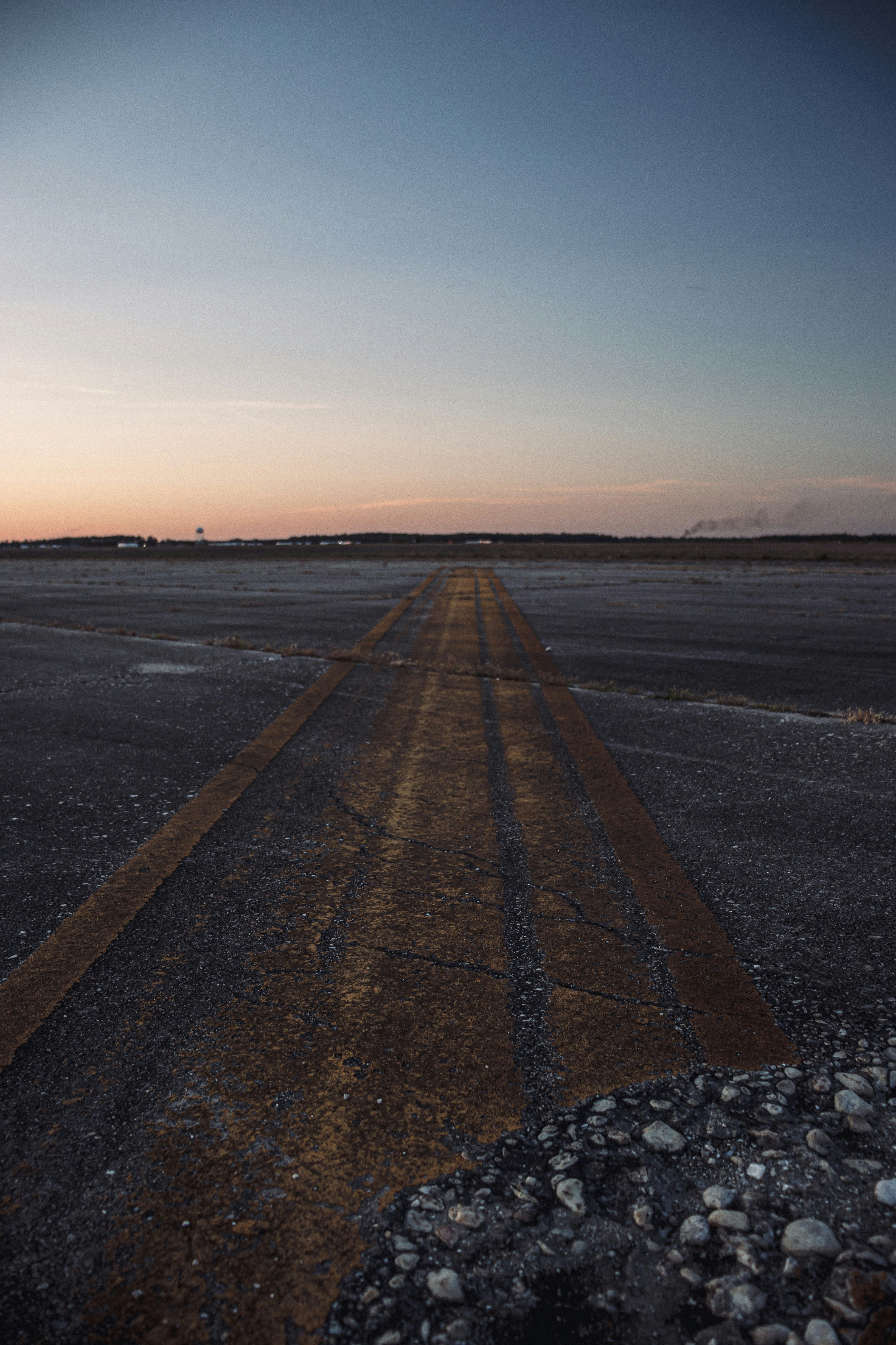 Cracked asphalt runway leading into a serene horizon at dusk, hinting at stories of journeys past.
