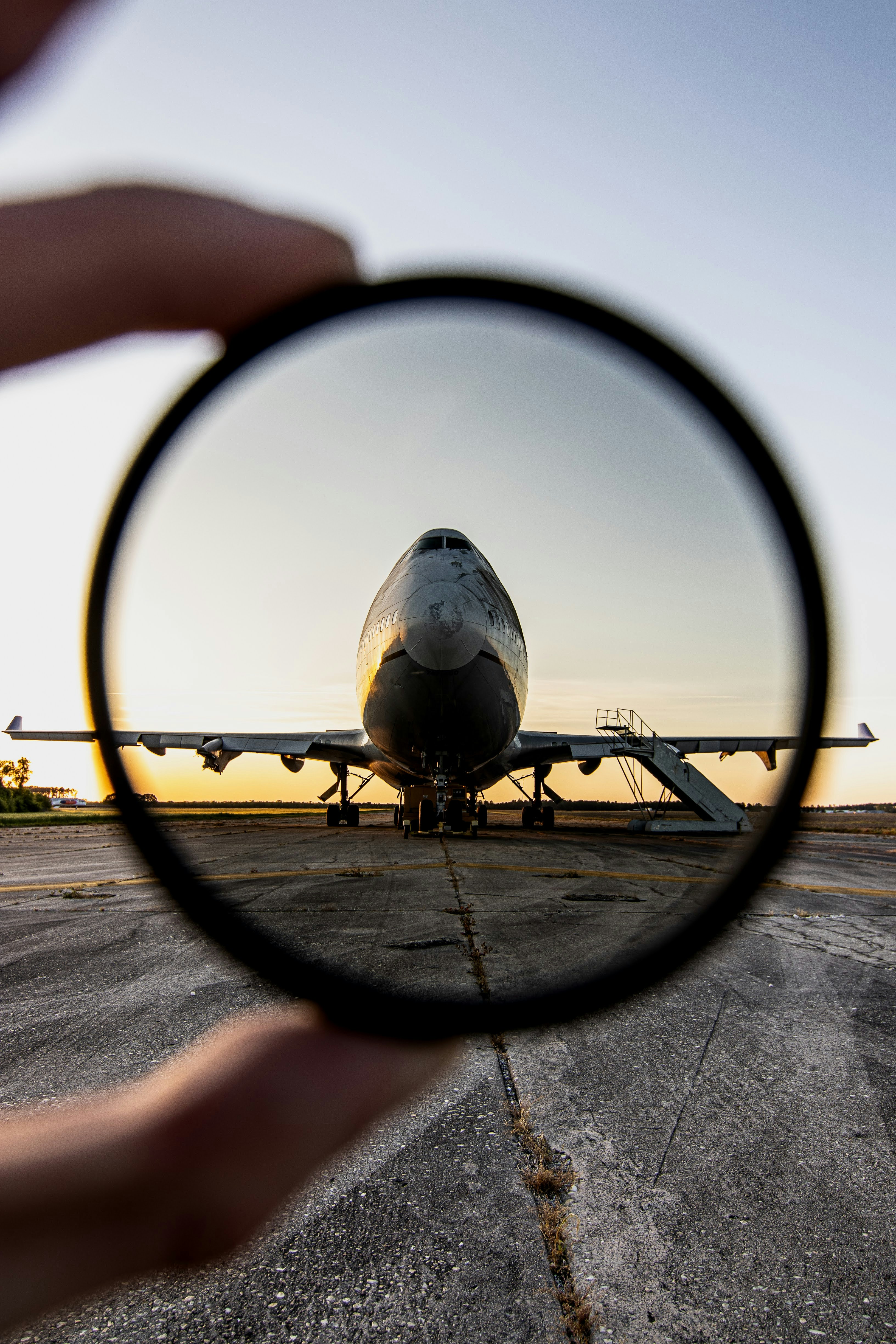 a person holding a magnifying glass looking at an airplane