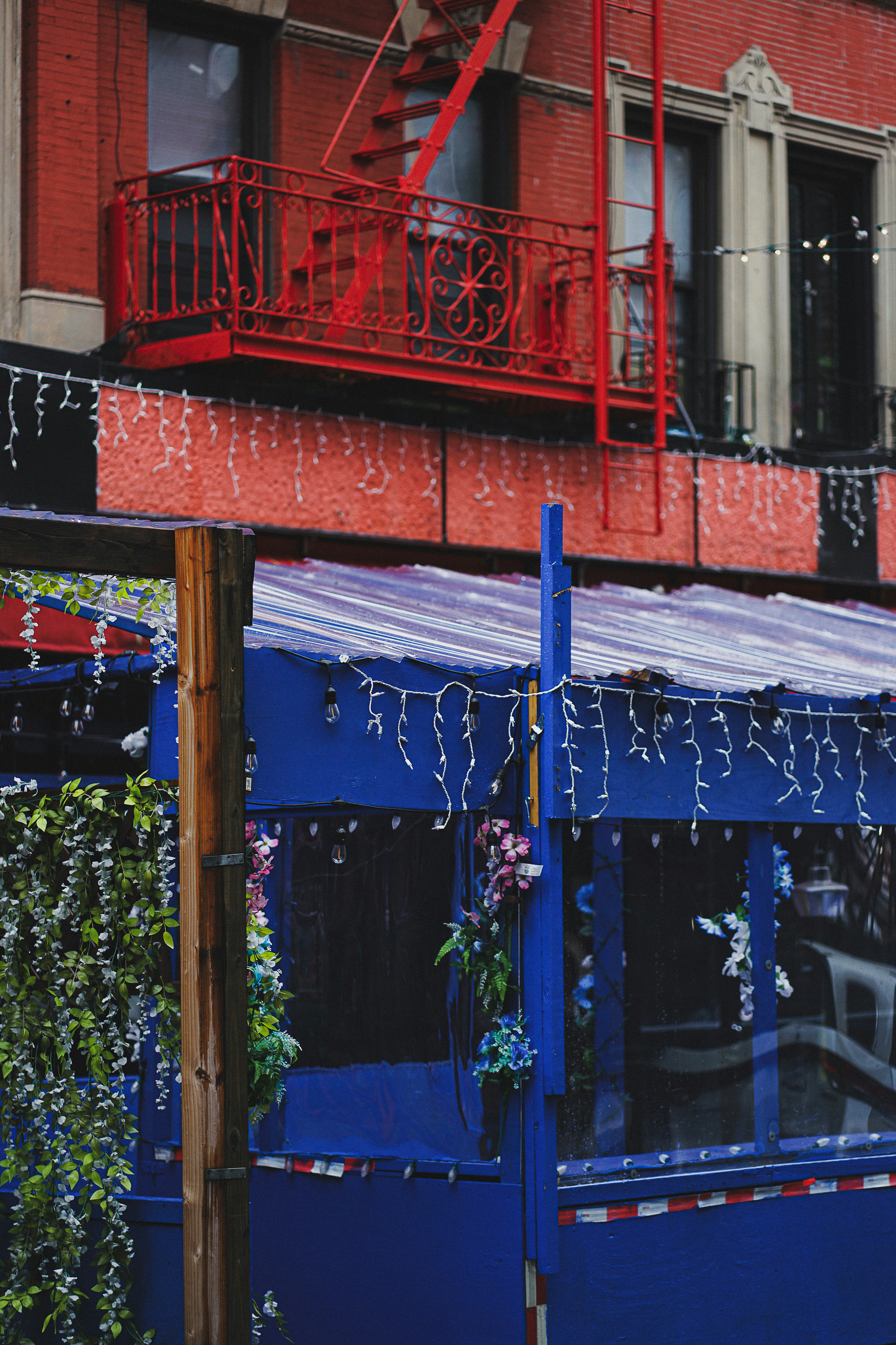 Blue Bistro Facade: Floral Garland and Fire Escape on a City Street