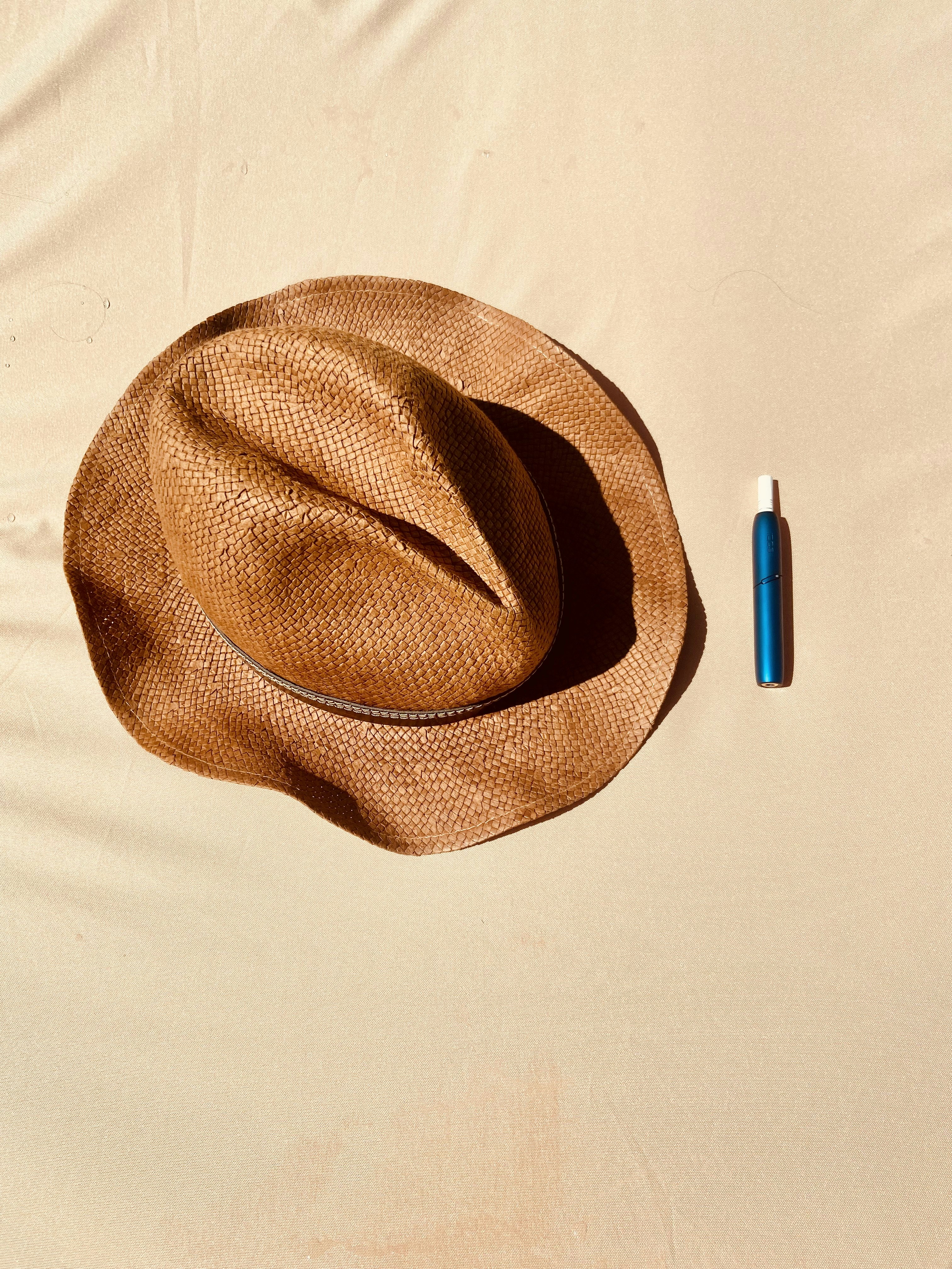 a straw hat and a blue pen on a white sheet