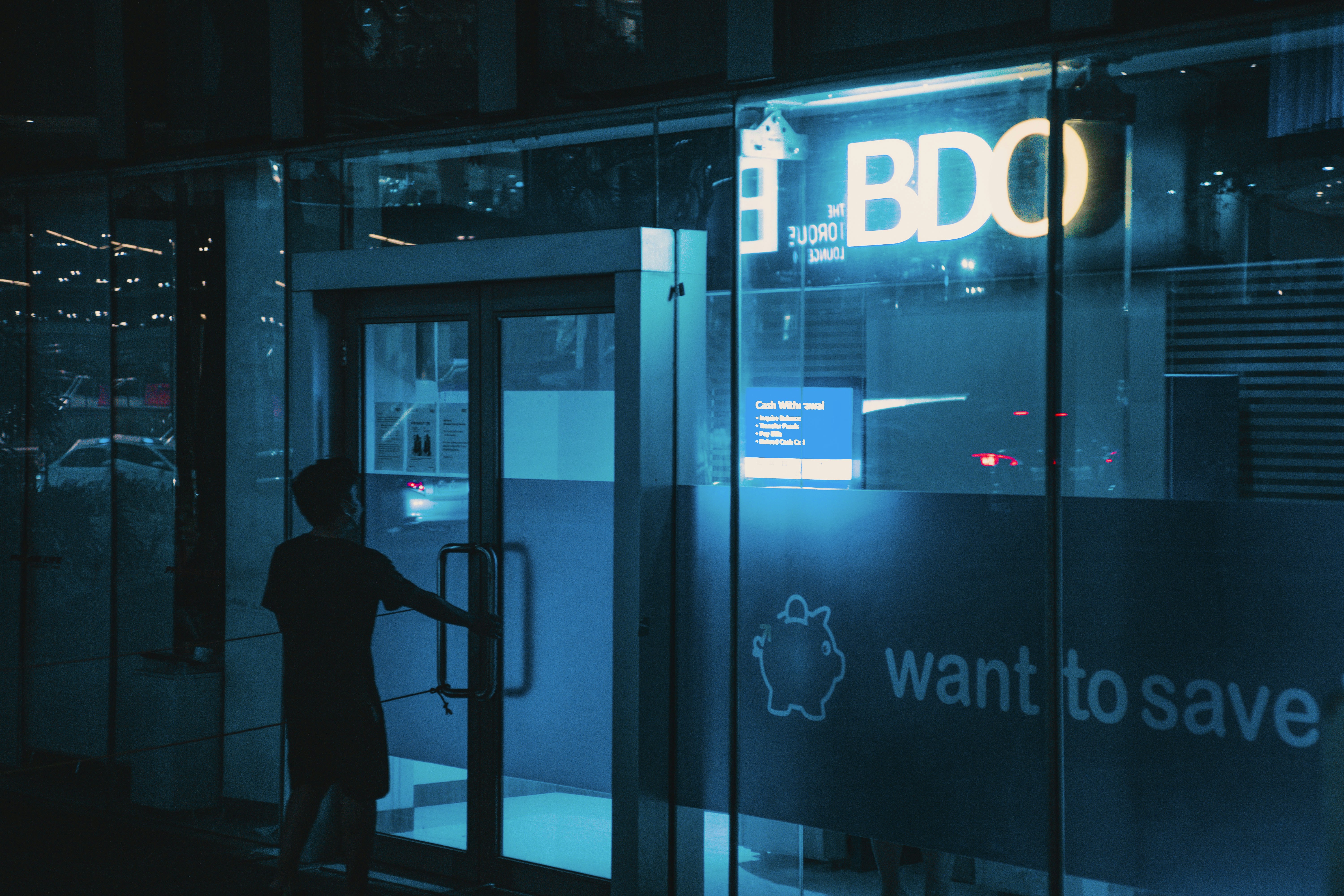 A person standing outside of a building at night photo – Free Blue ...