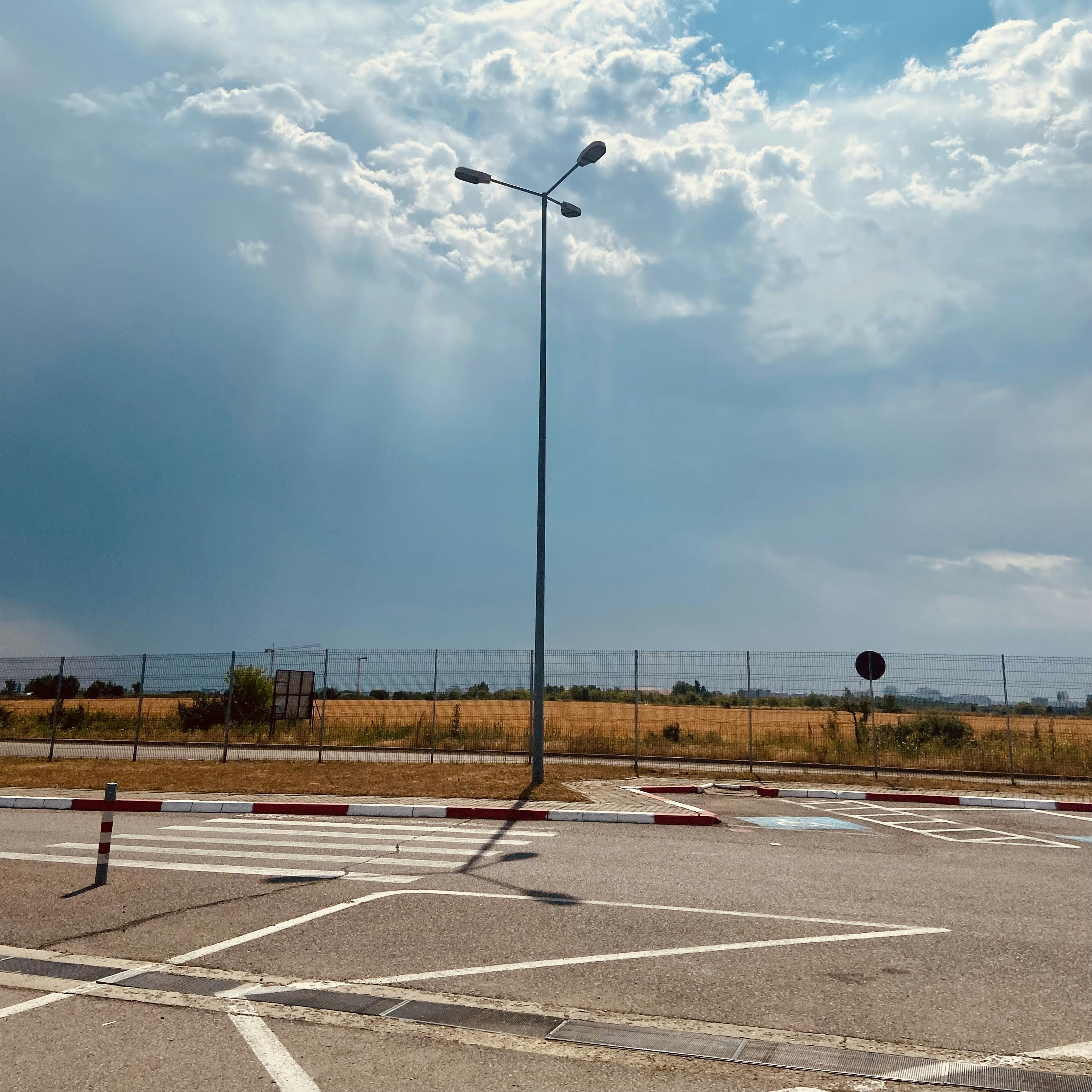Central Streetlamp Framed by a Dramatic Cloudscape Over a Quiet Parking Area