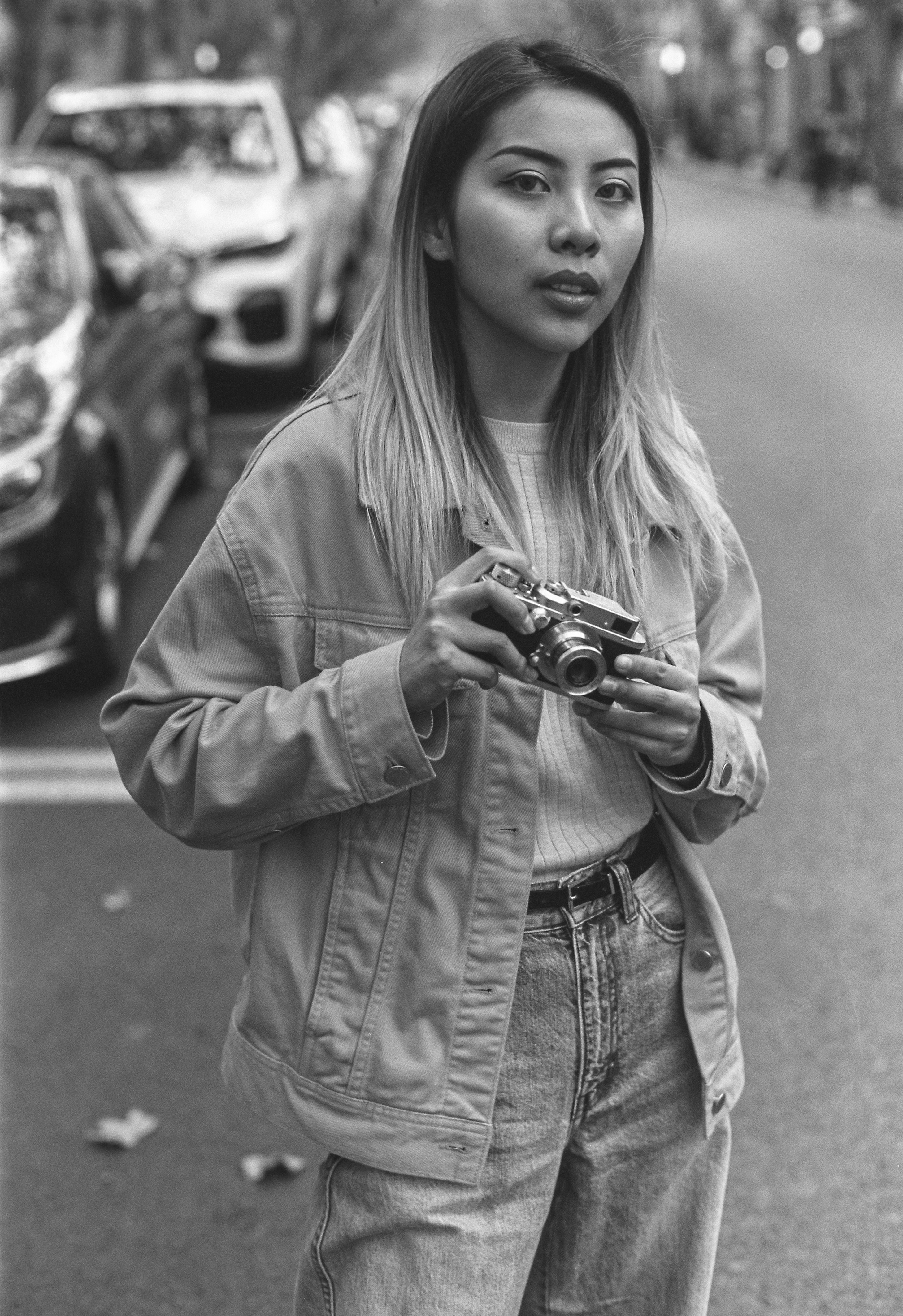 Monochrome Street Portrait: A Woman with a Vintage Camera on a City Street